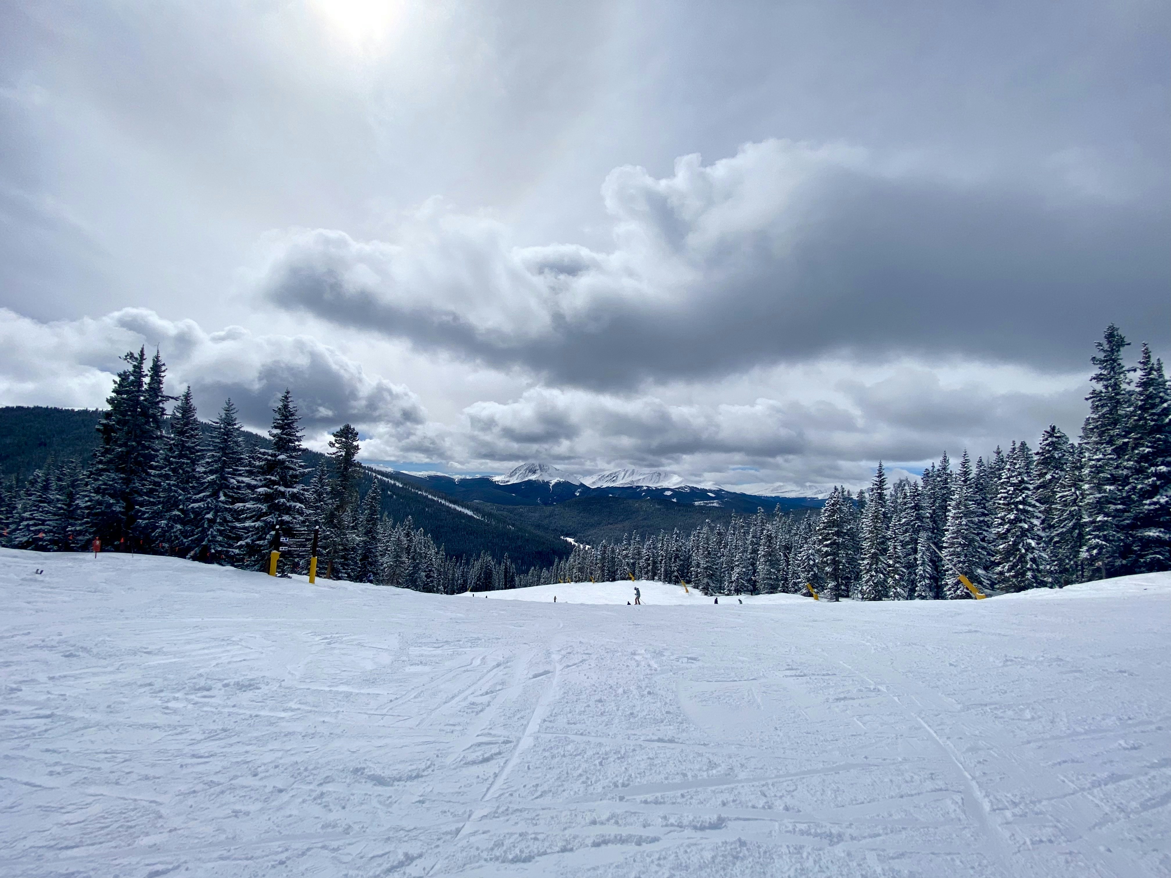 A snow covered ski slope with trees in the background photo – Free ...