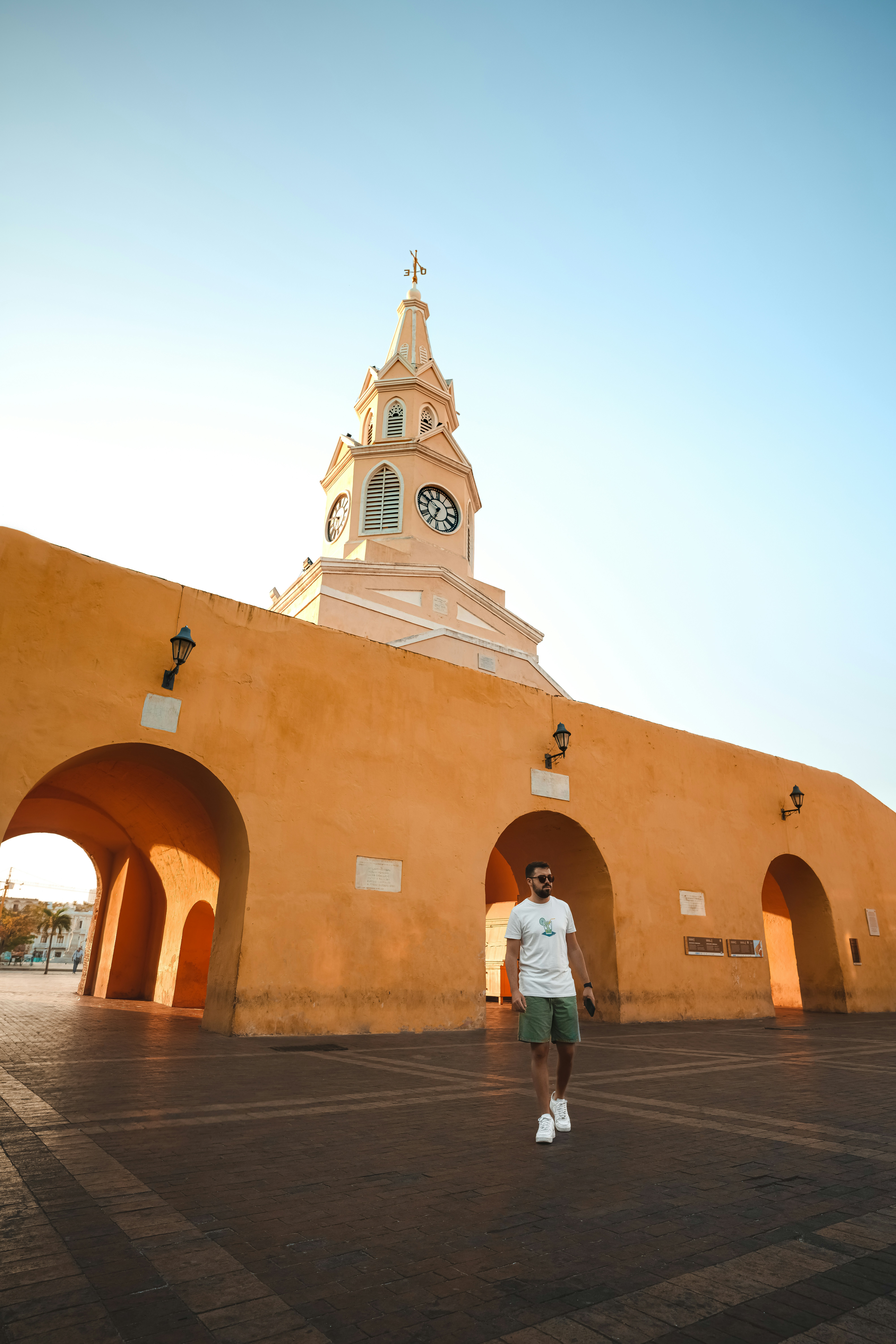 a man standing in front of a building with a clock tower