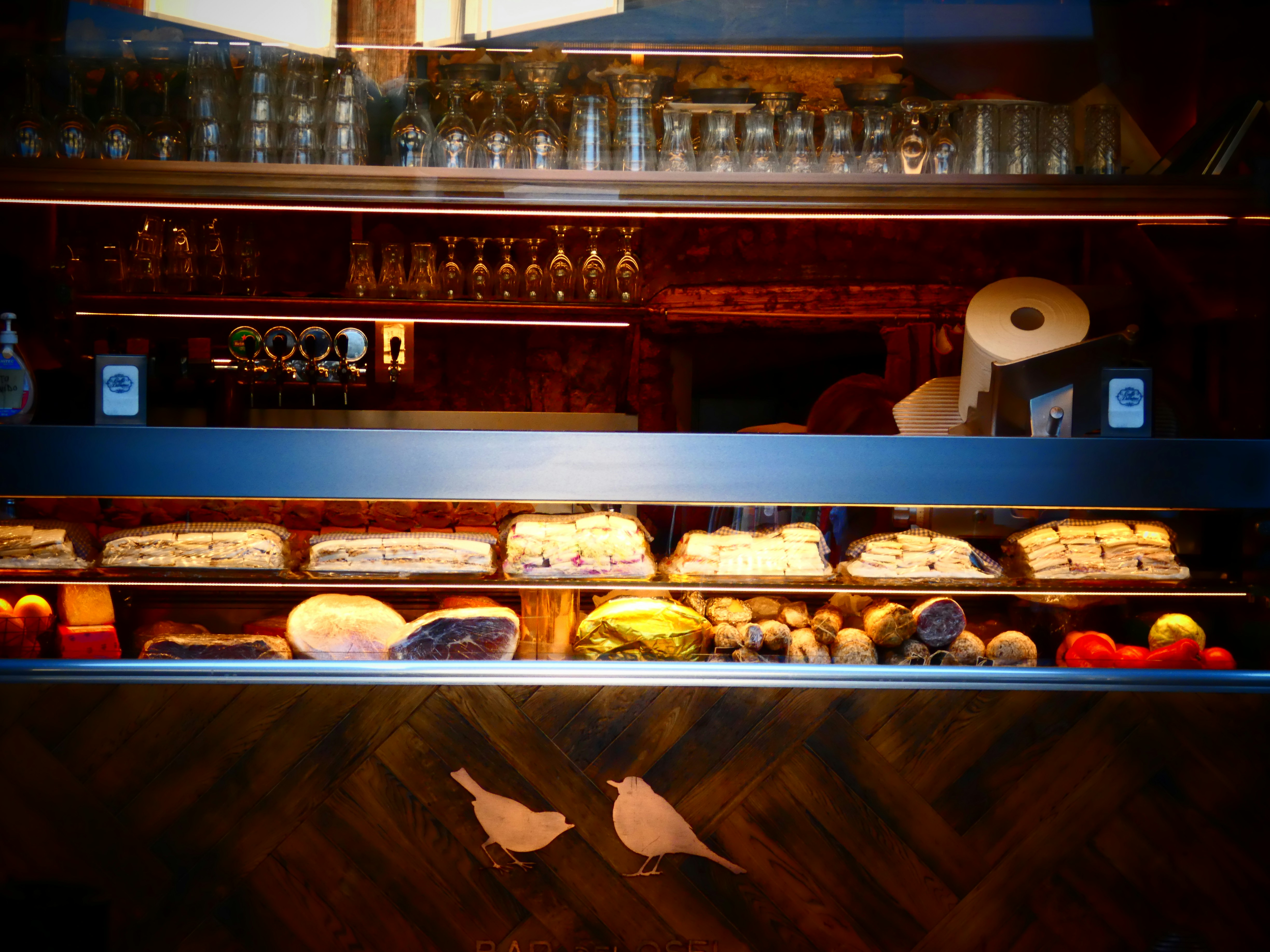 Warm Display Case: Breads and Birds Beneath Glass and Blue Shelf