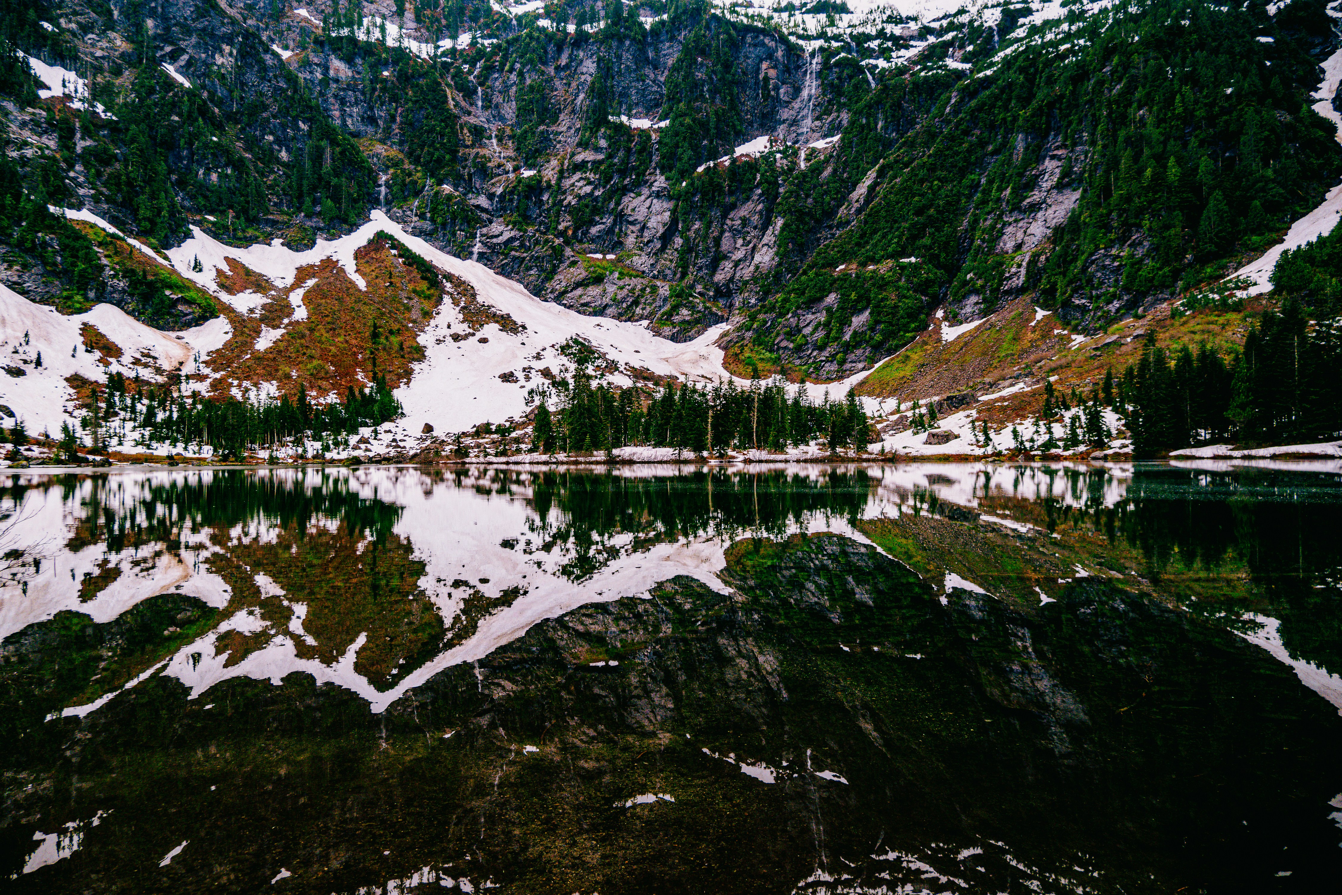Snow-dusted mountains reflecting perfectly in a serene alpine lake.