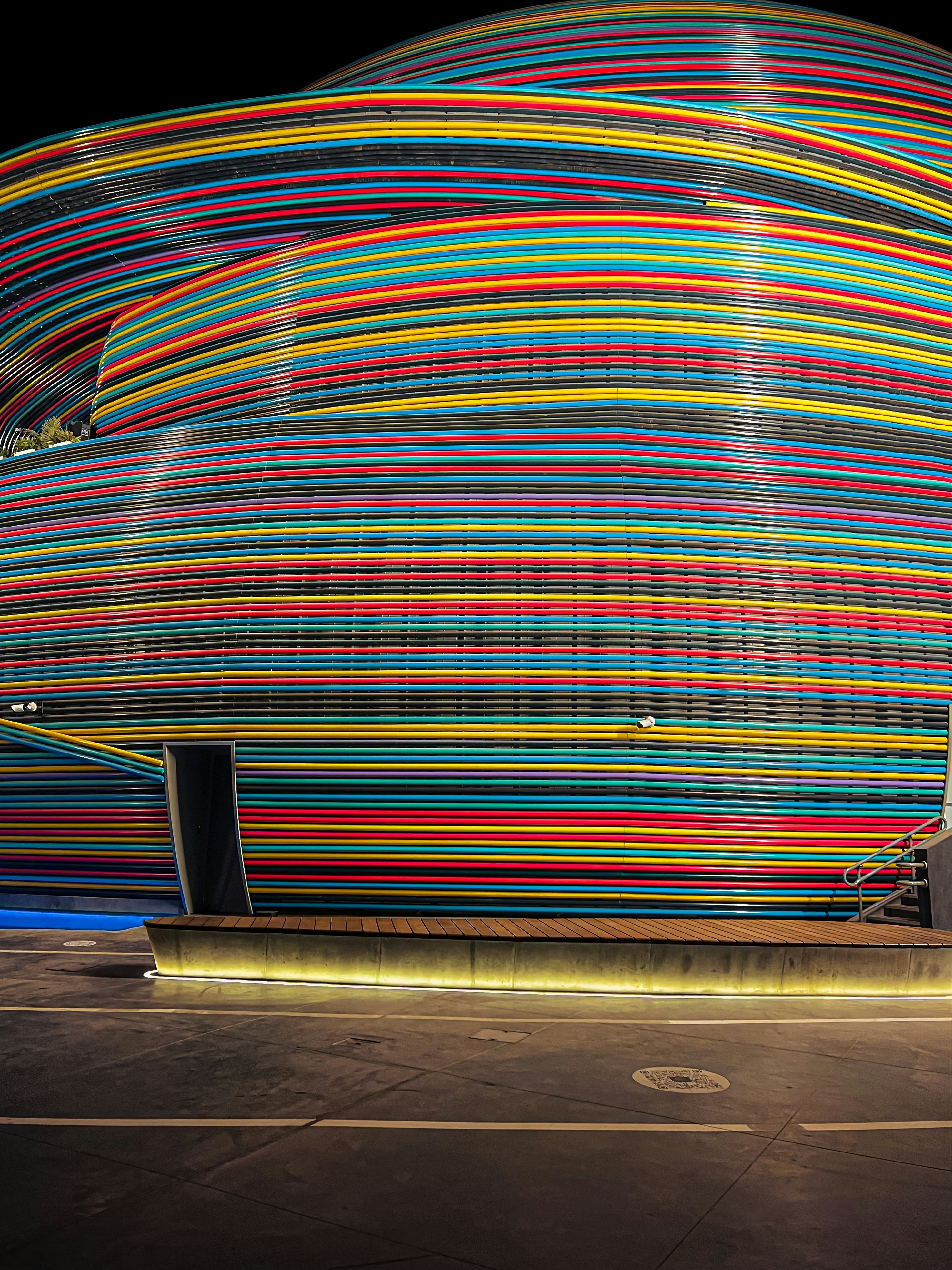 Neon Ribbon Dome at Night: A Curved Facade of Colorful Stripes