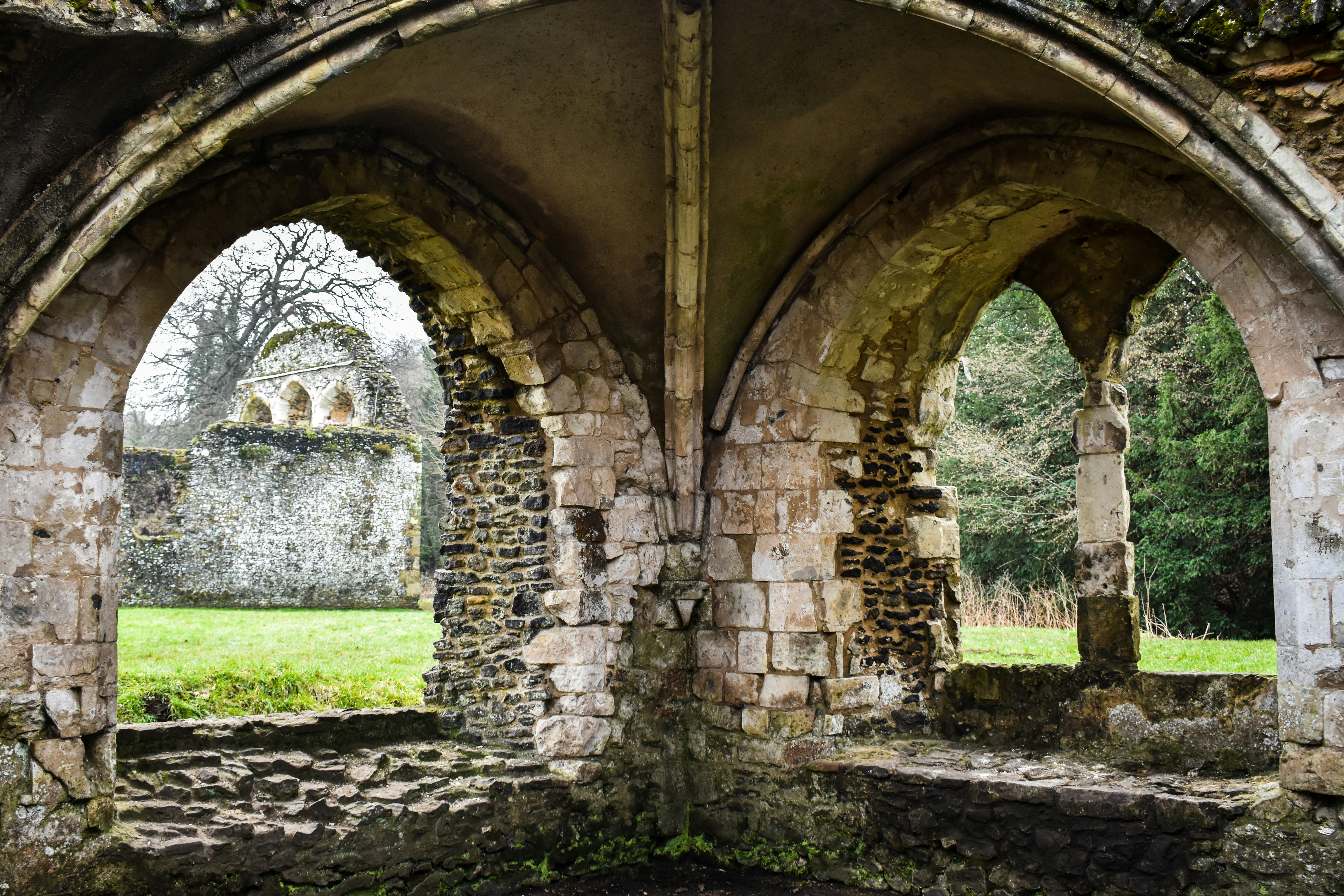 an old stone building with arches and a grassy field in the background