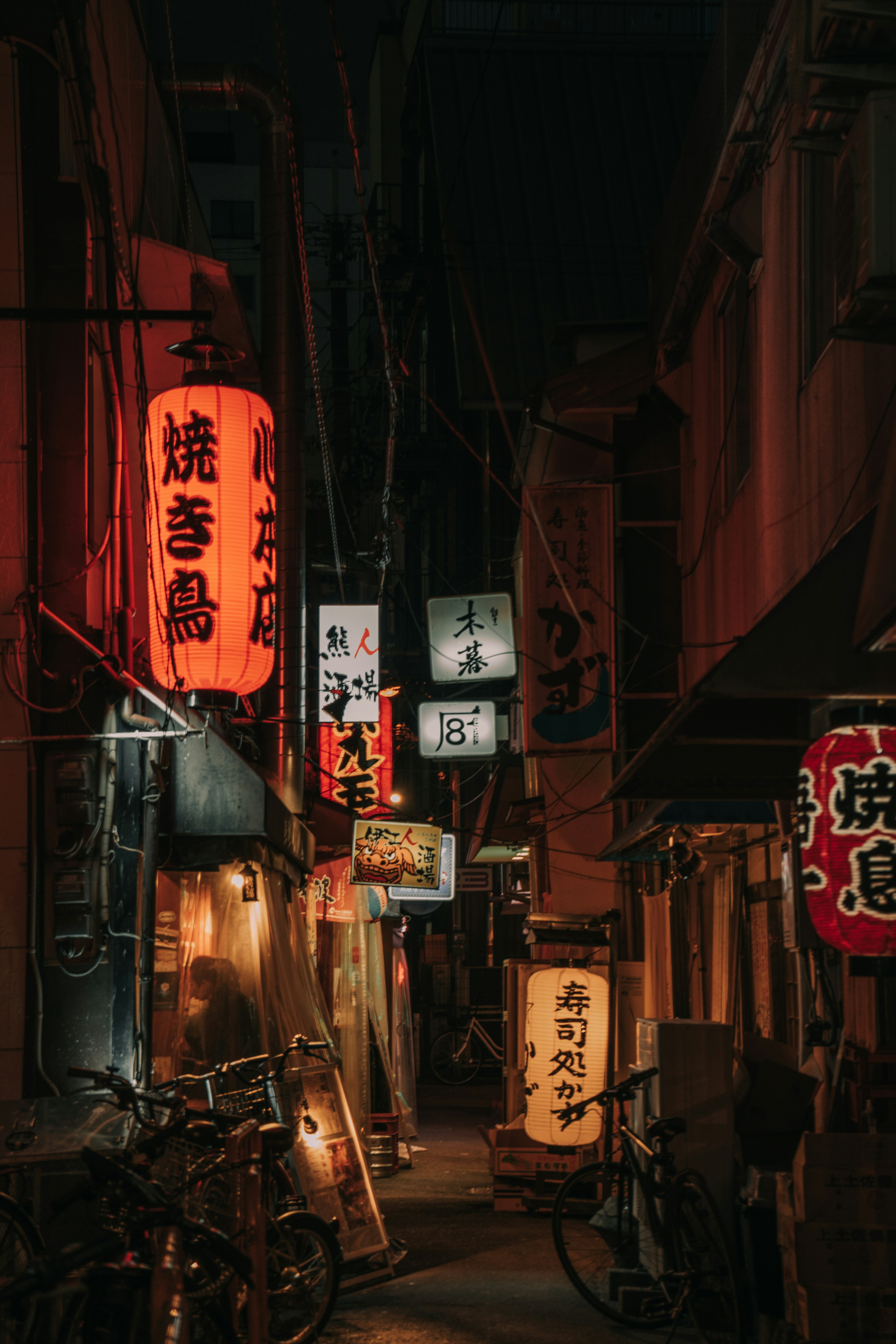 A narrow alley with signs and bicycles parked on the side of it photo ...