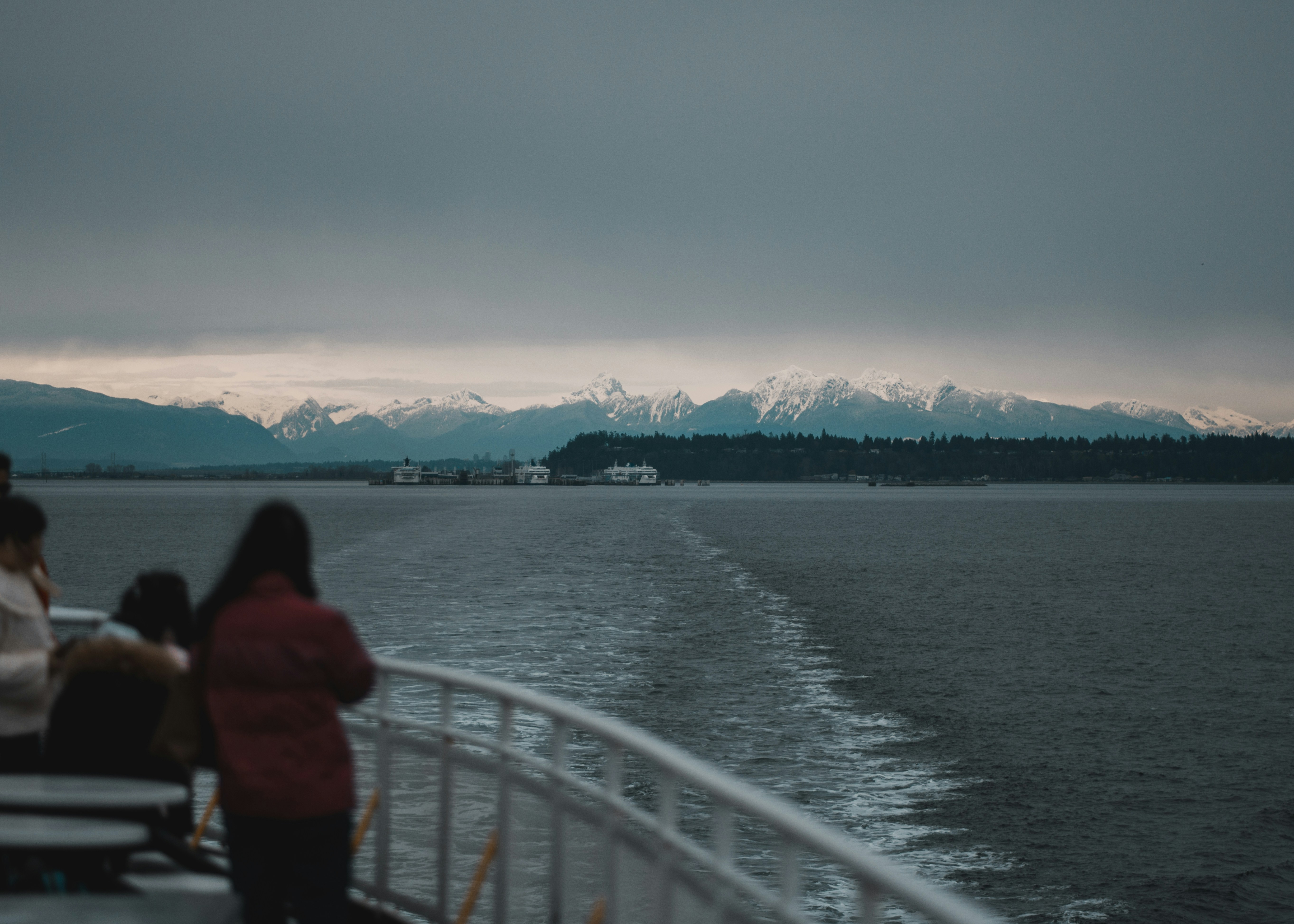 Snow-Capped Horizon: The Ferry's Wake Across Quiet Waters