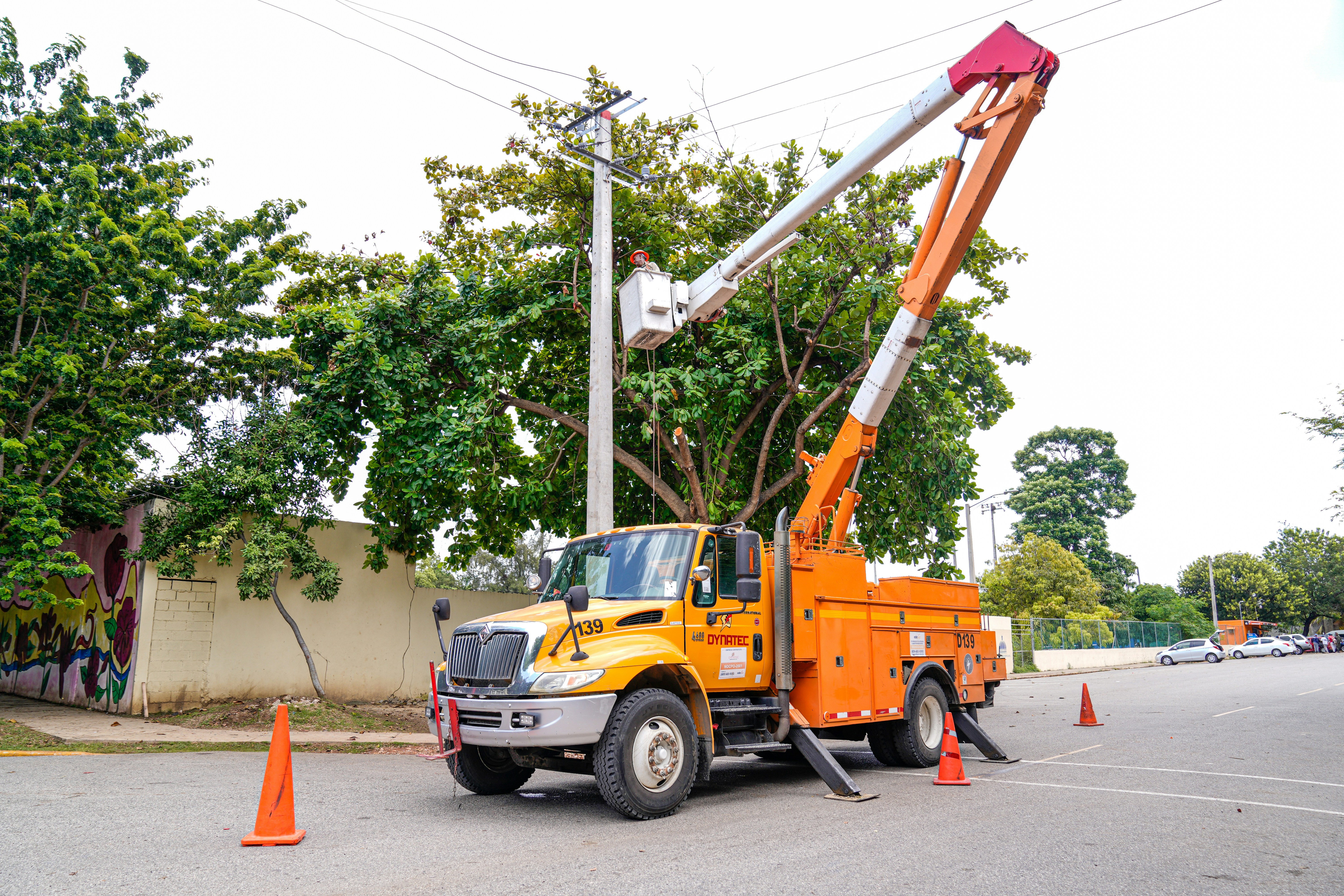 Orange Aerial Lift on a Quiet Street: Cones, Graffiti and Maintenance Readiness