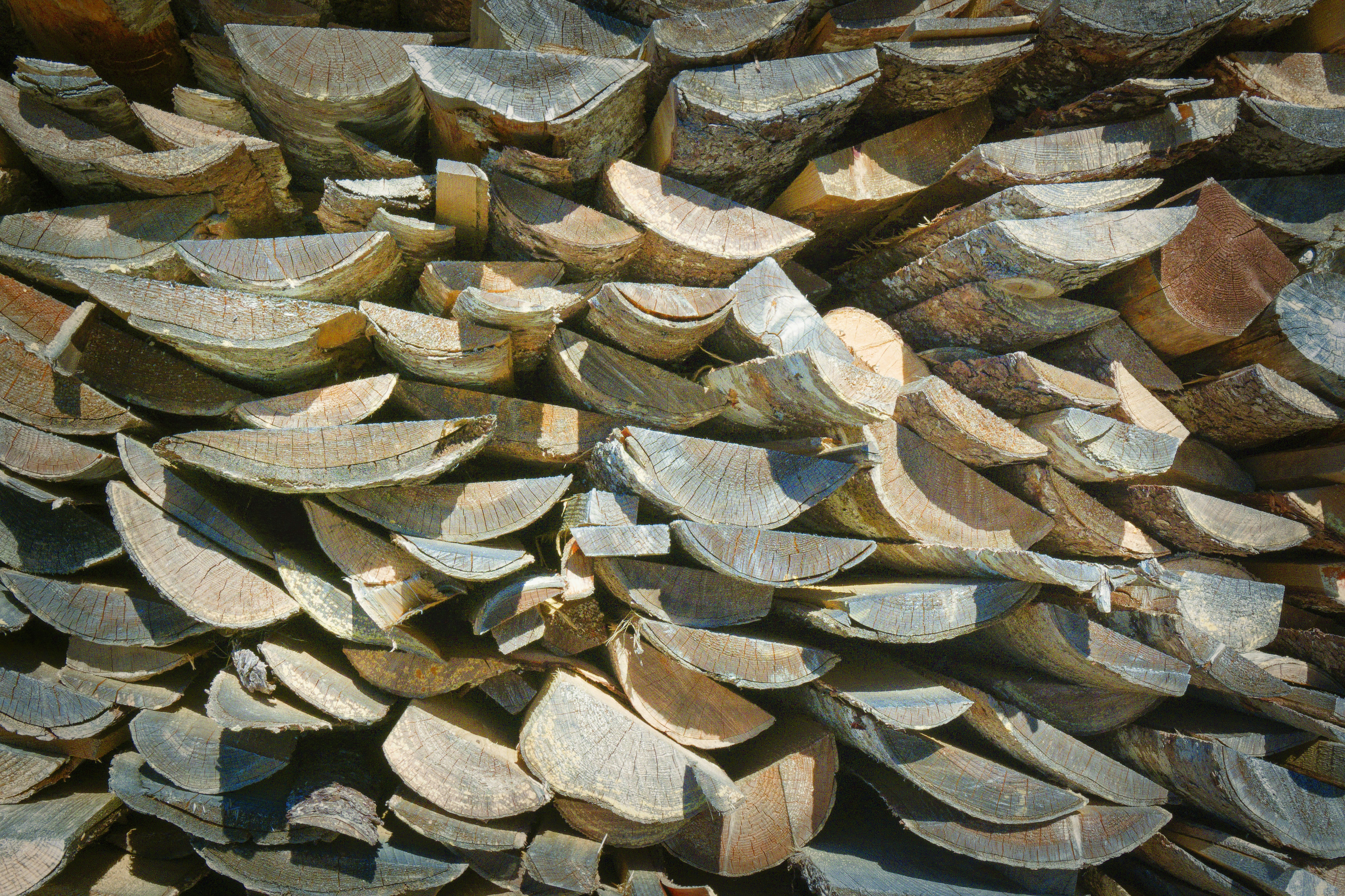 A close-up view of neatly stacked logs, showcasing their varied textures and colors. The arrangement highlights the craftsmanship and natural beauty of wood.