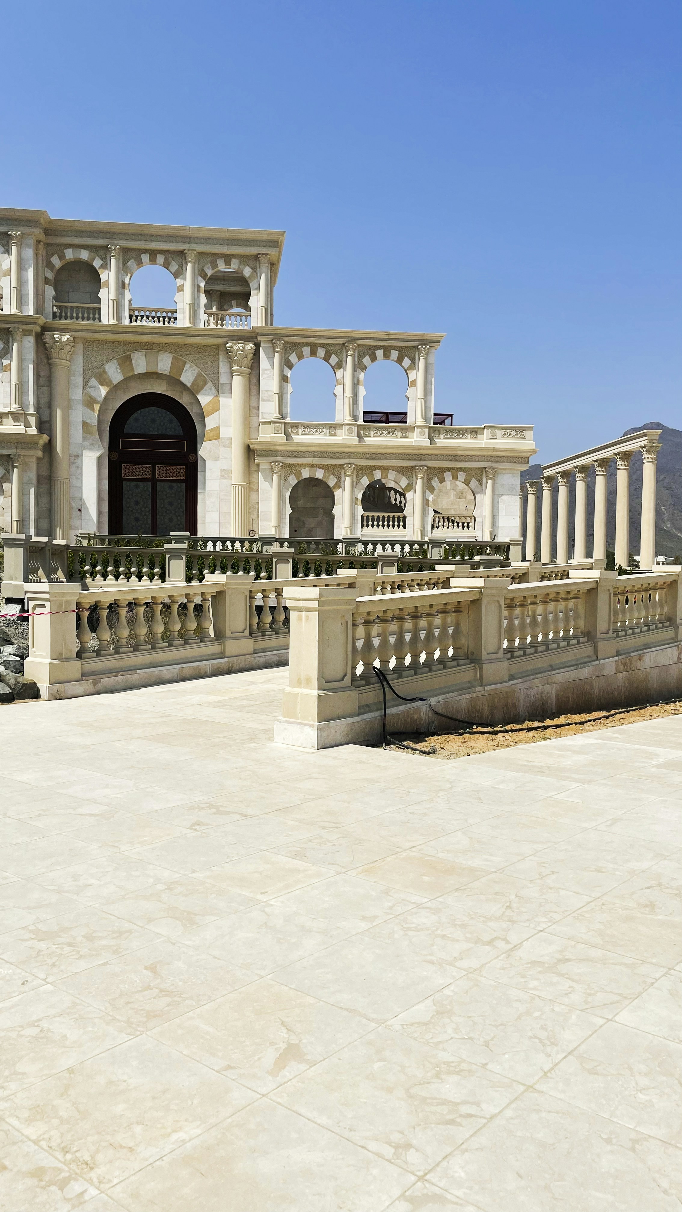 Sunlit Archways: A Limestone Terrace Framed by Repeating Arches