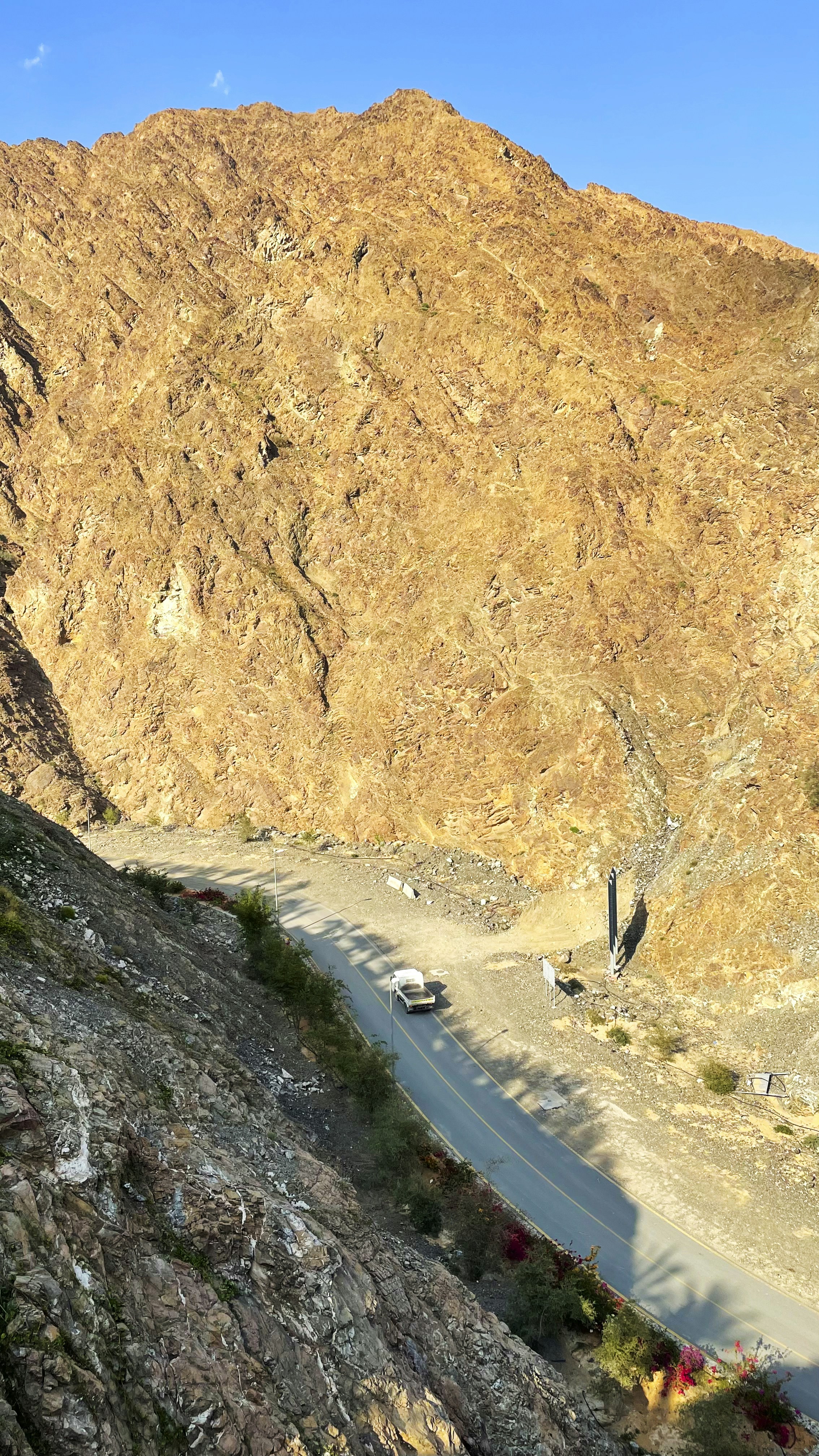 Desert Mountain Pass: A Car Winds Through Golden Rock Faces
