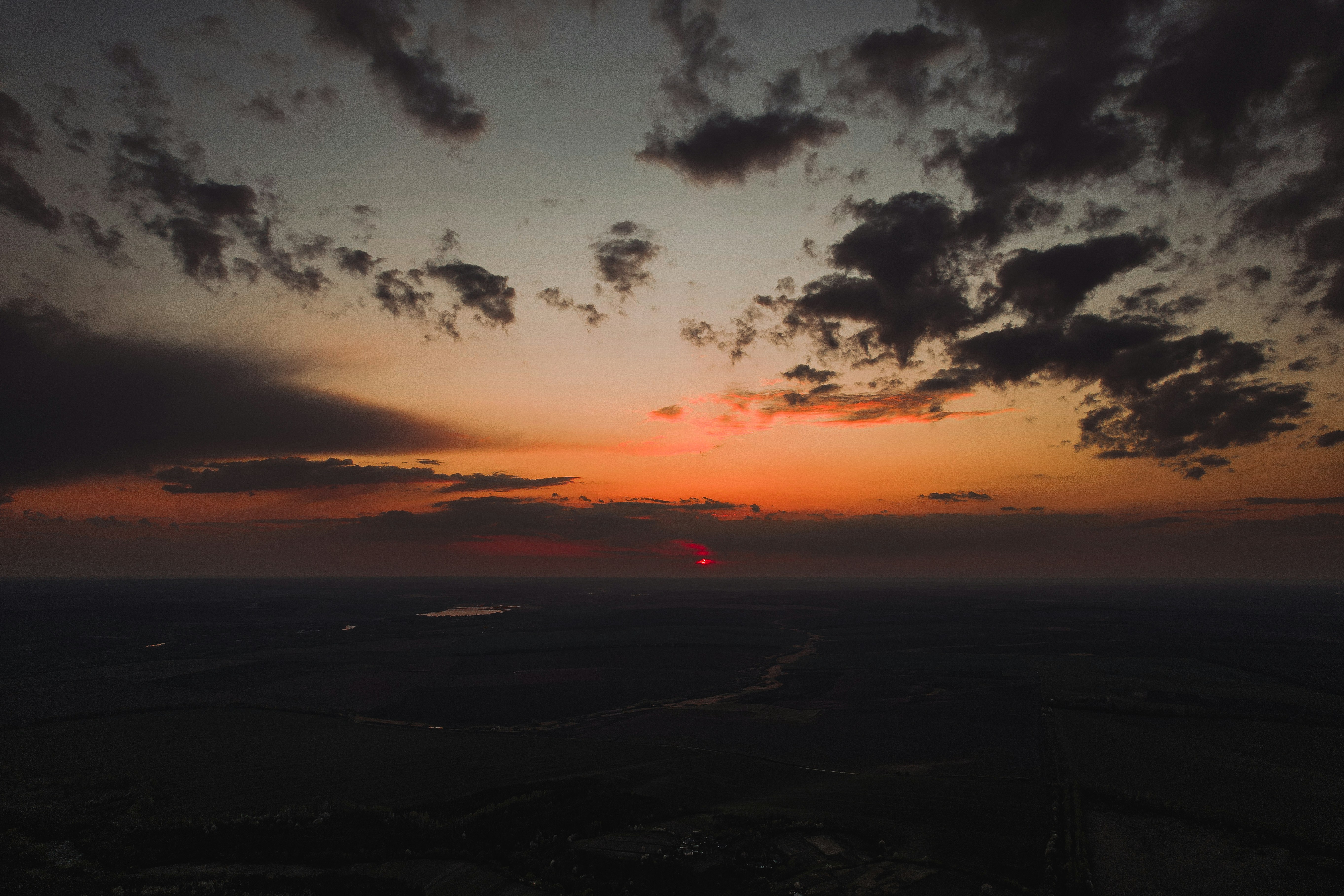 Sunset casting warm hues over a vast water body with scattered clouds.