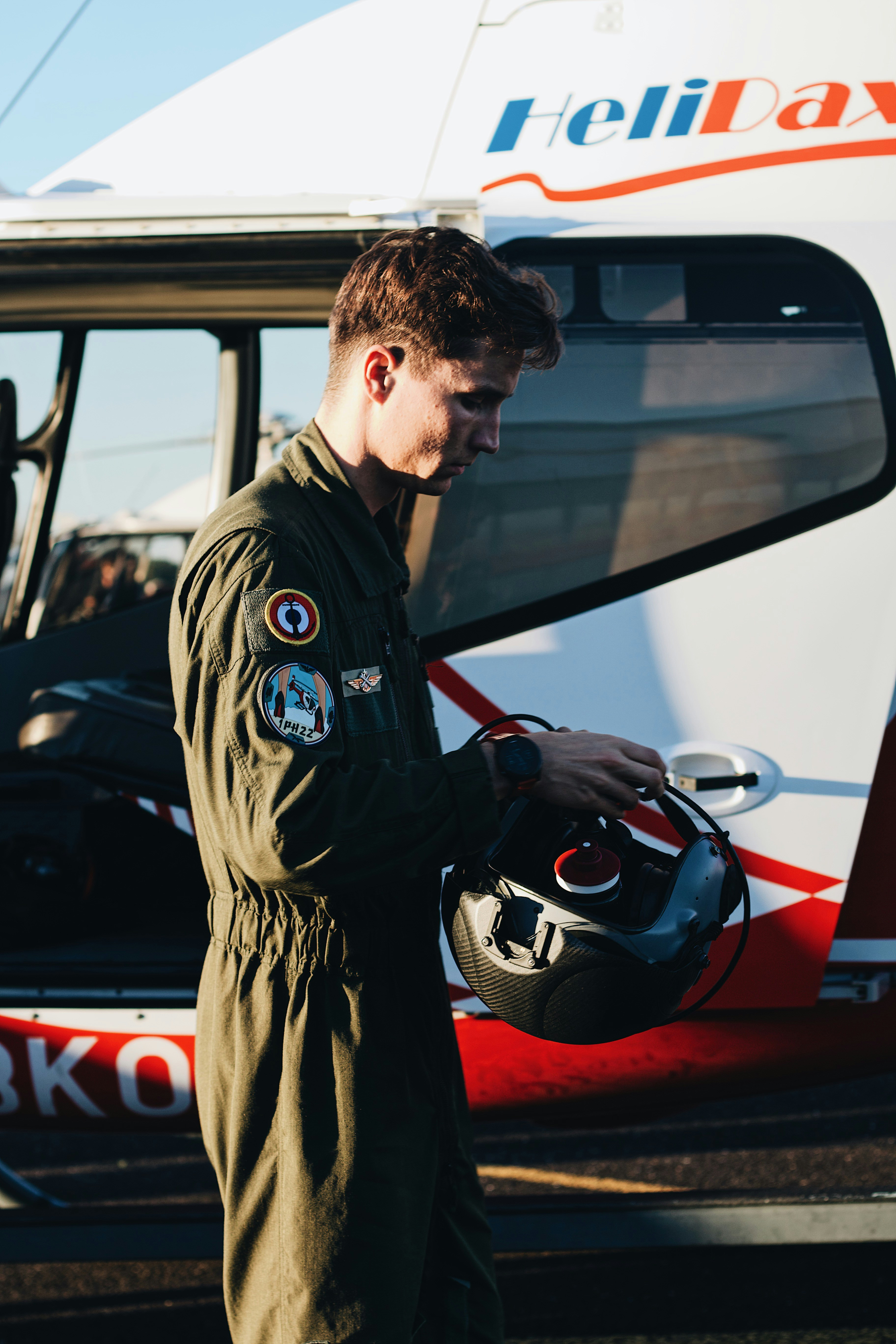 A man in a pilot's uniform standing in front of a helicopter photo ...