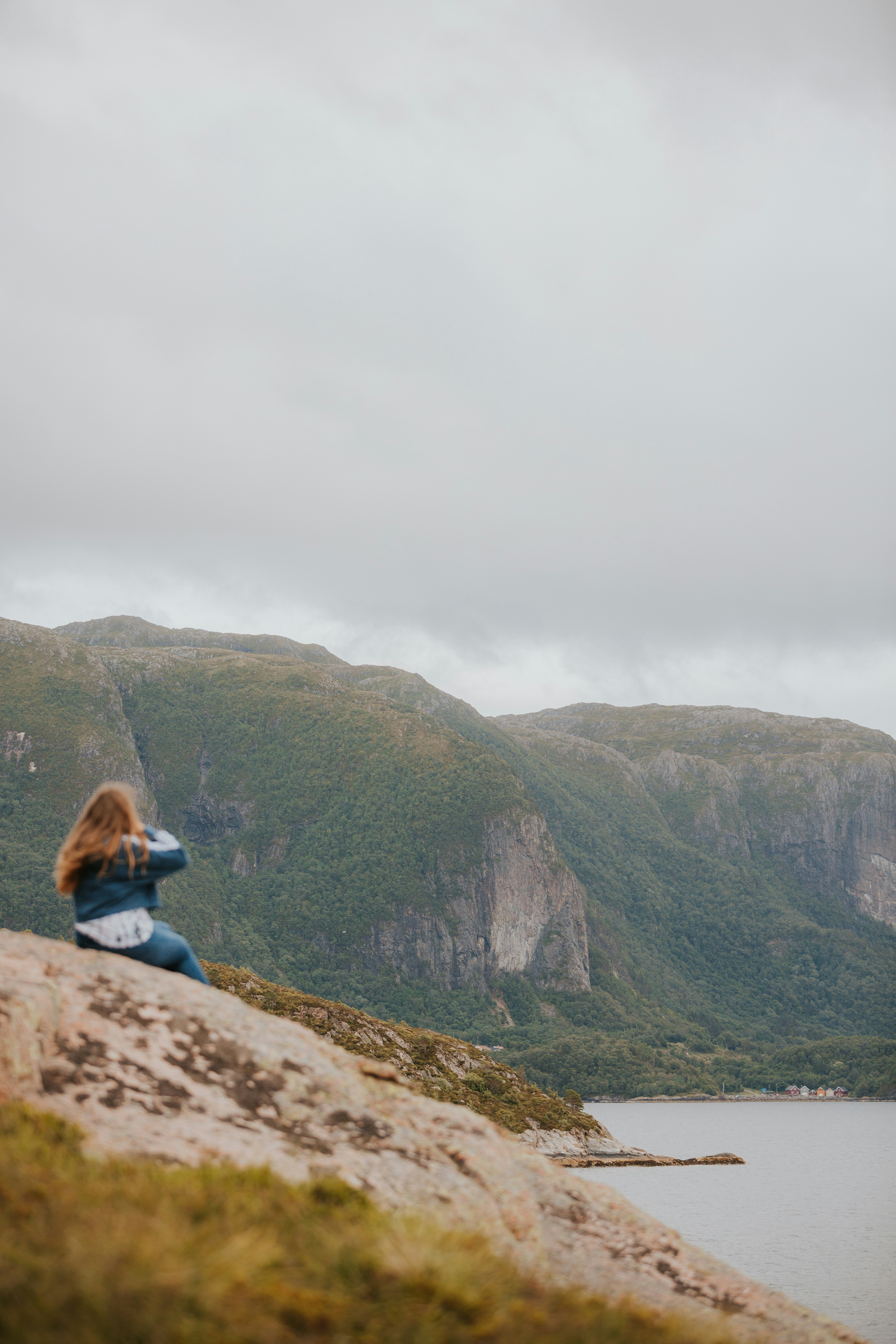 a woman sitting on top of a rock next to a body of water