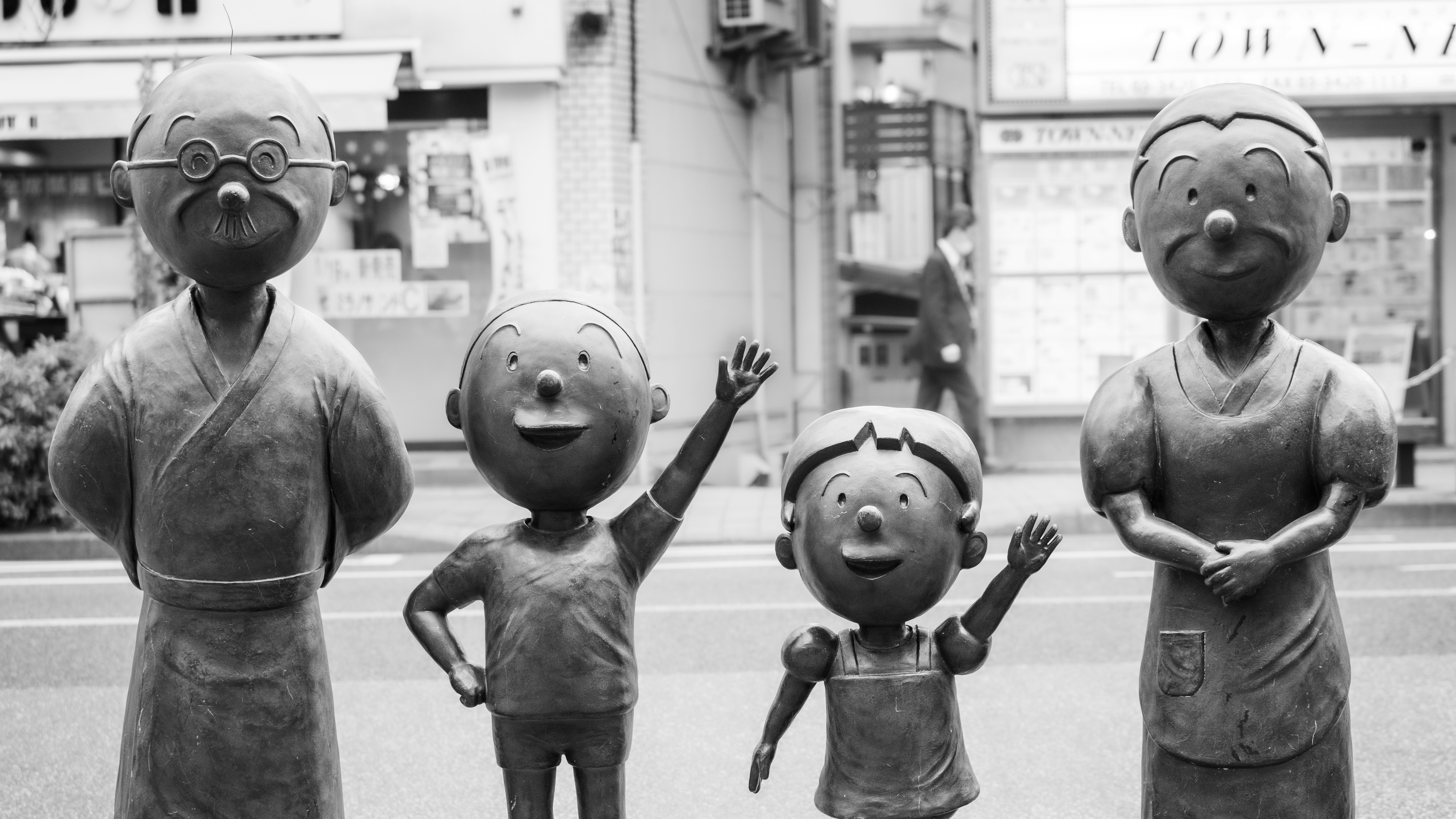 Sidewalk Quartet: Four Round-Headed Statues Guard a Quiet Street