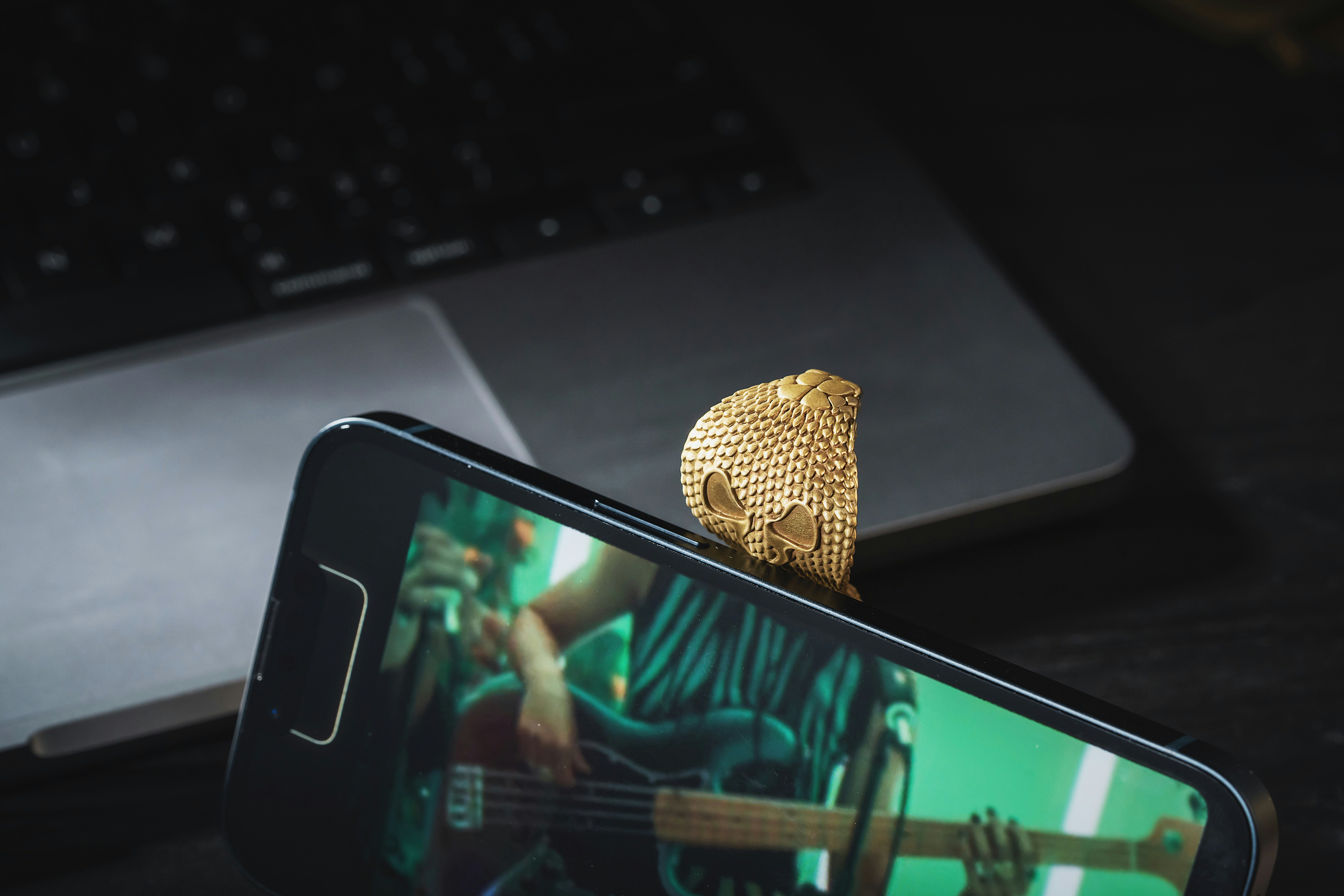 Gilded Perch: A Golden Figurine Balances on a Smartphone Display