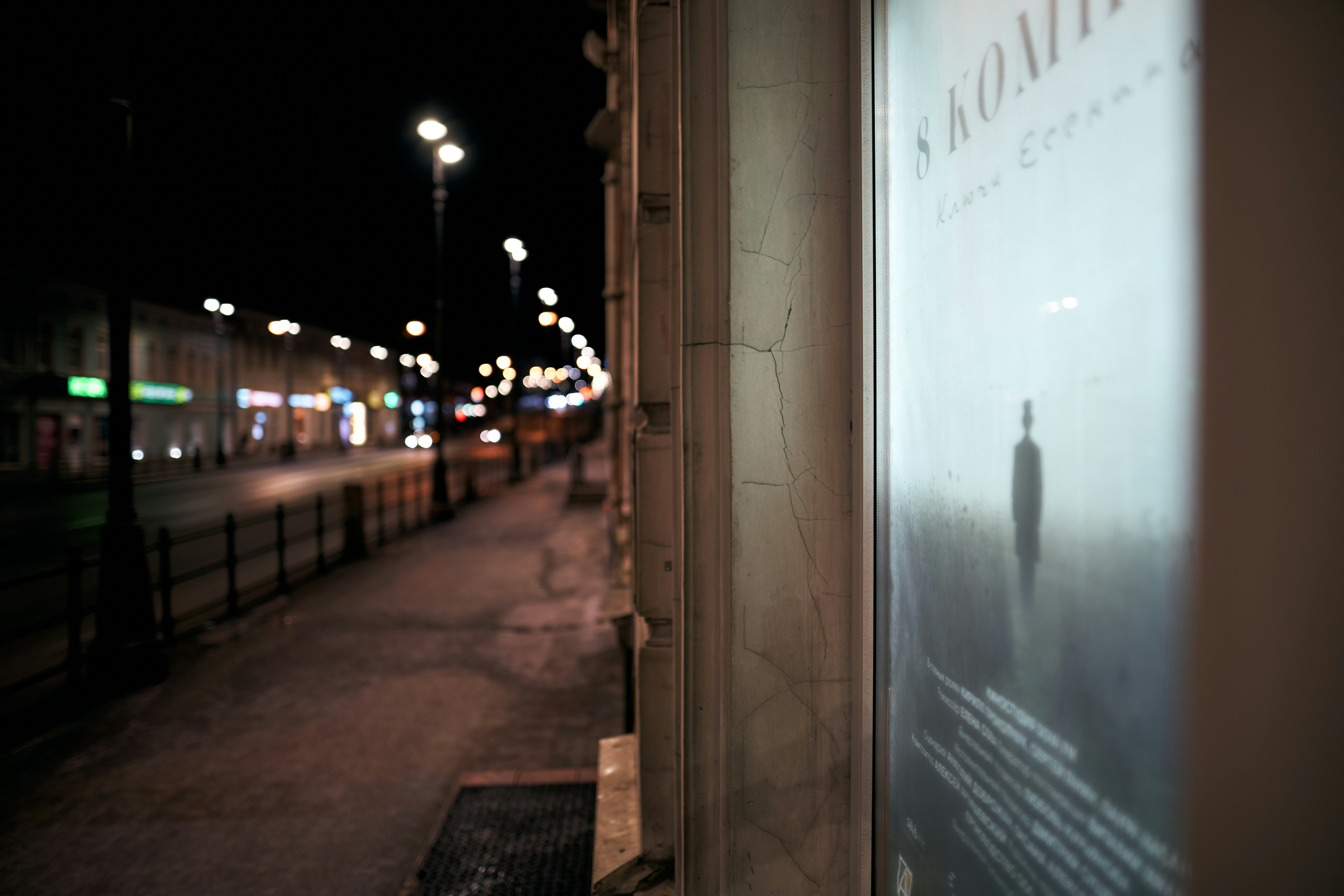 Silhouette on Glass: A Night Street Framed by Neon Bokeh