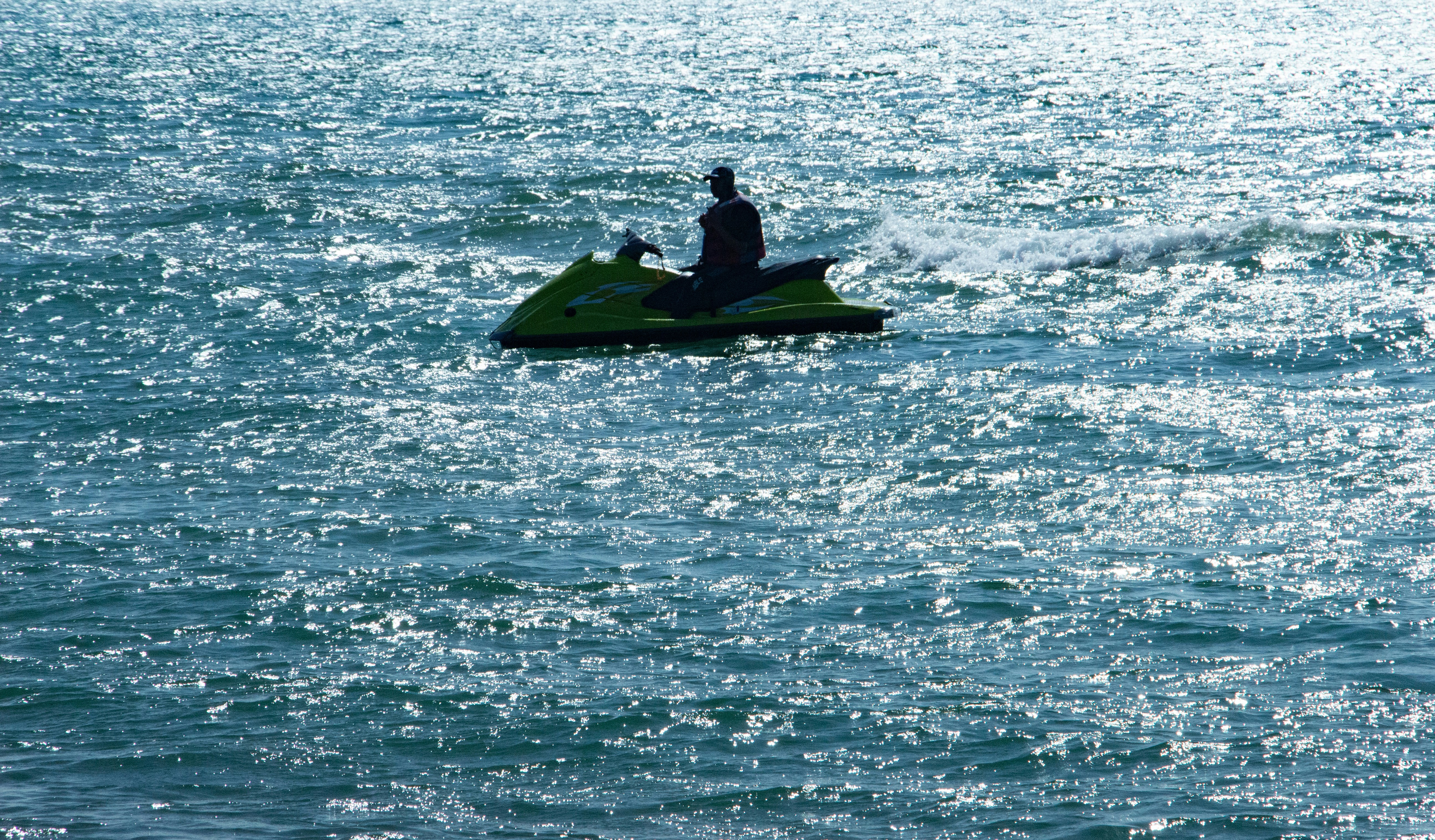 Jet-Skier on Glittering Sea: A Momentary Silhouette Against Sunlit Crests