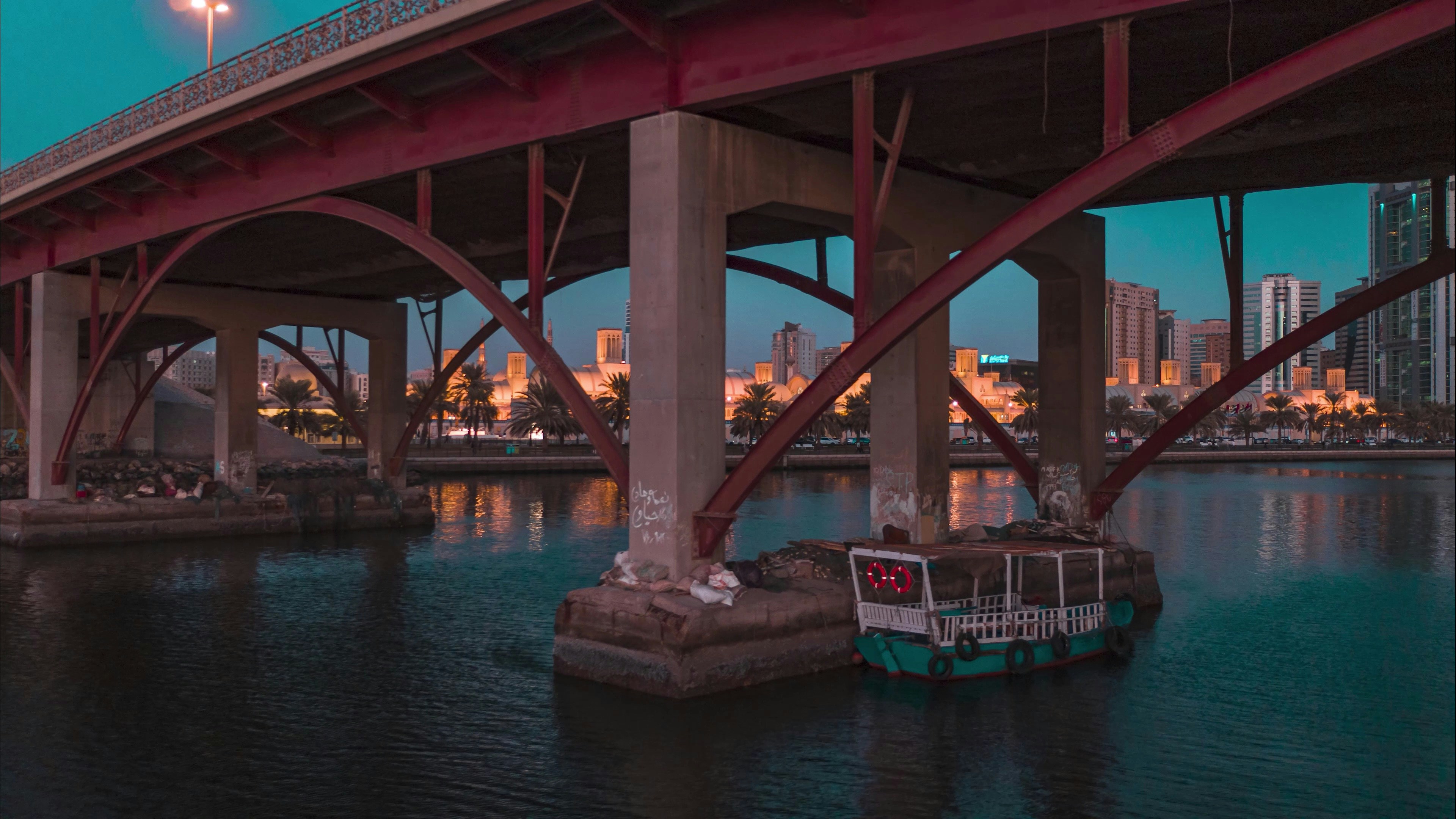 A boat that is sitting in the water under a bridge photo – Free Sharjah ...