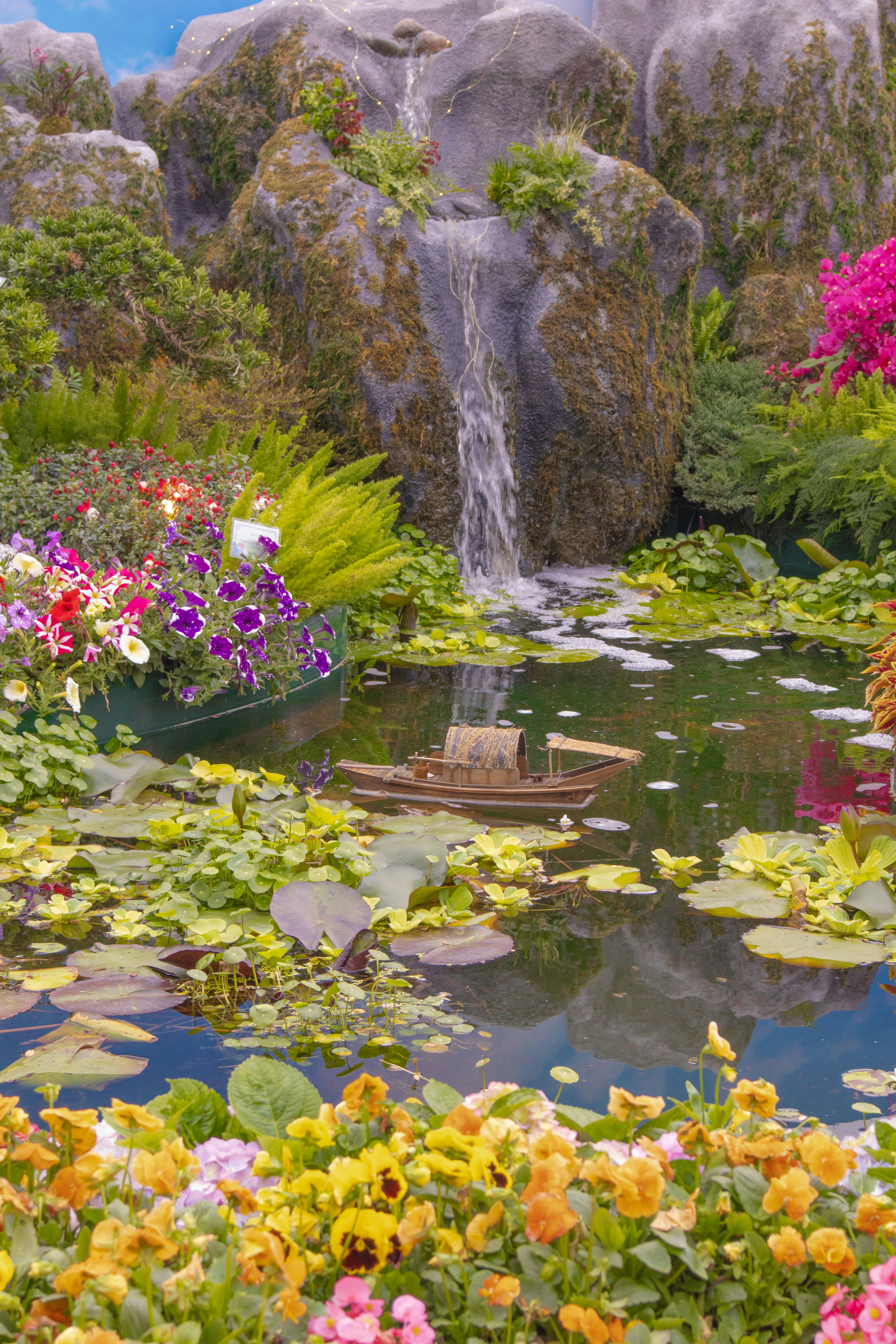 A pond filled with lots of flowers next to a waterfall photo – Free ...
