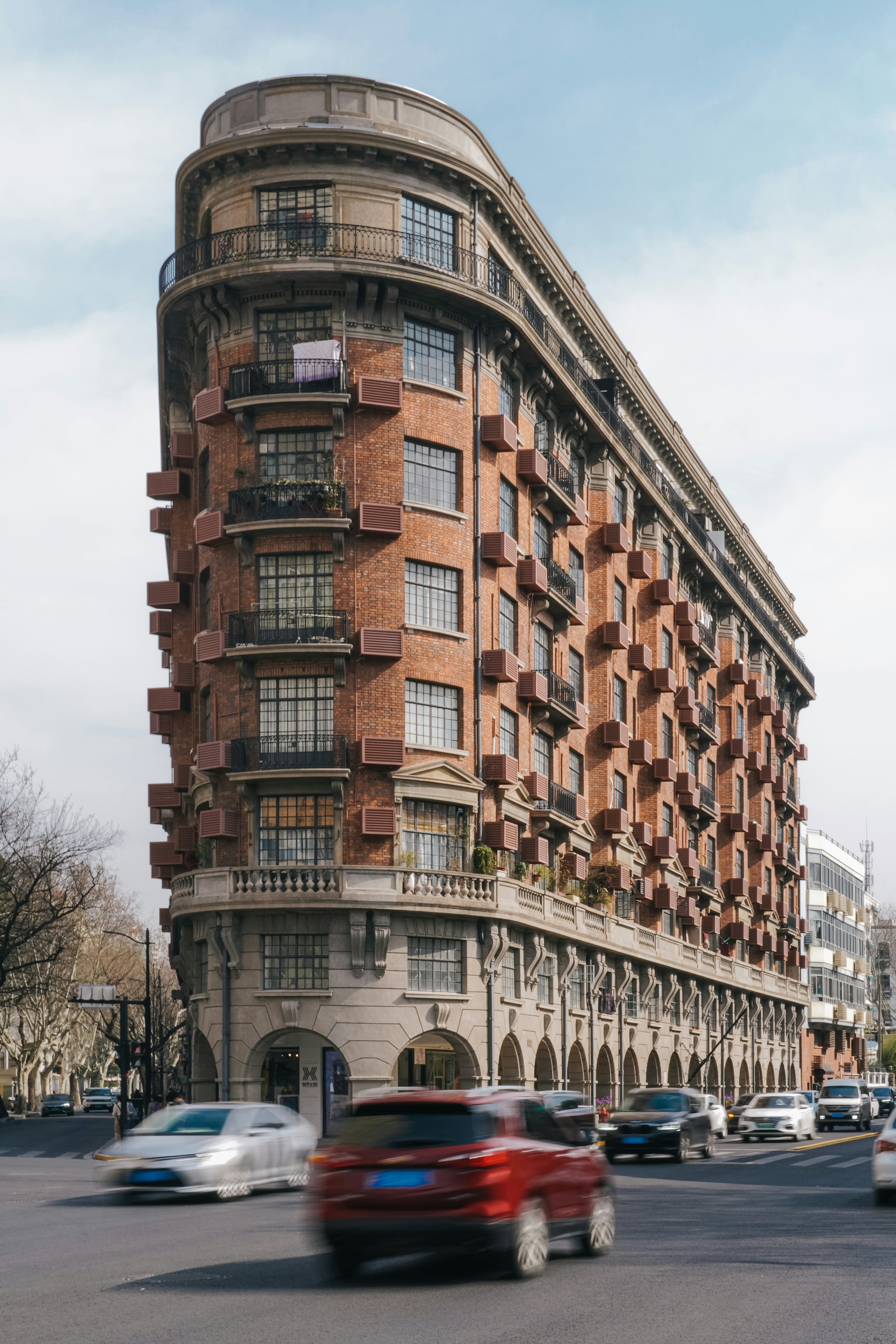 A red car driving down a street next to a tall building photo – Free ...