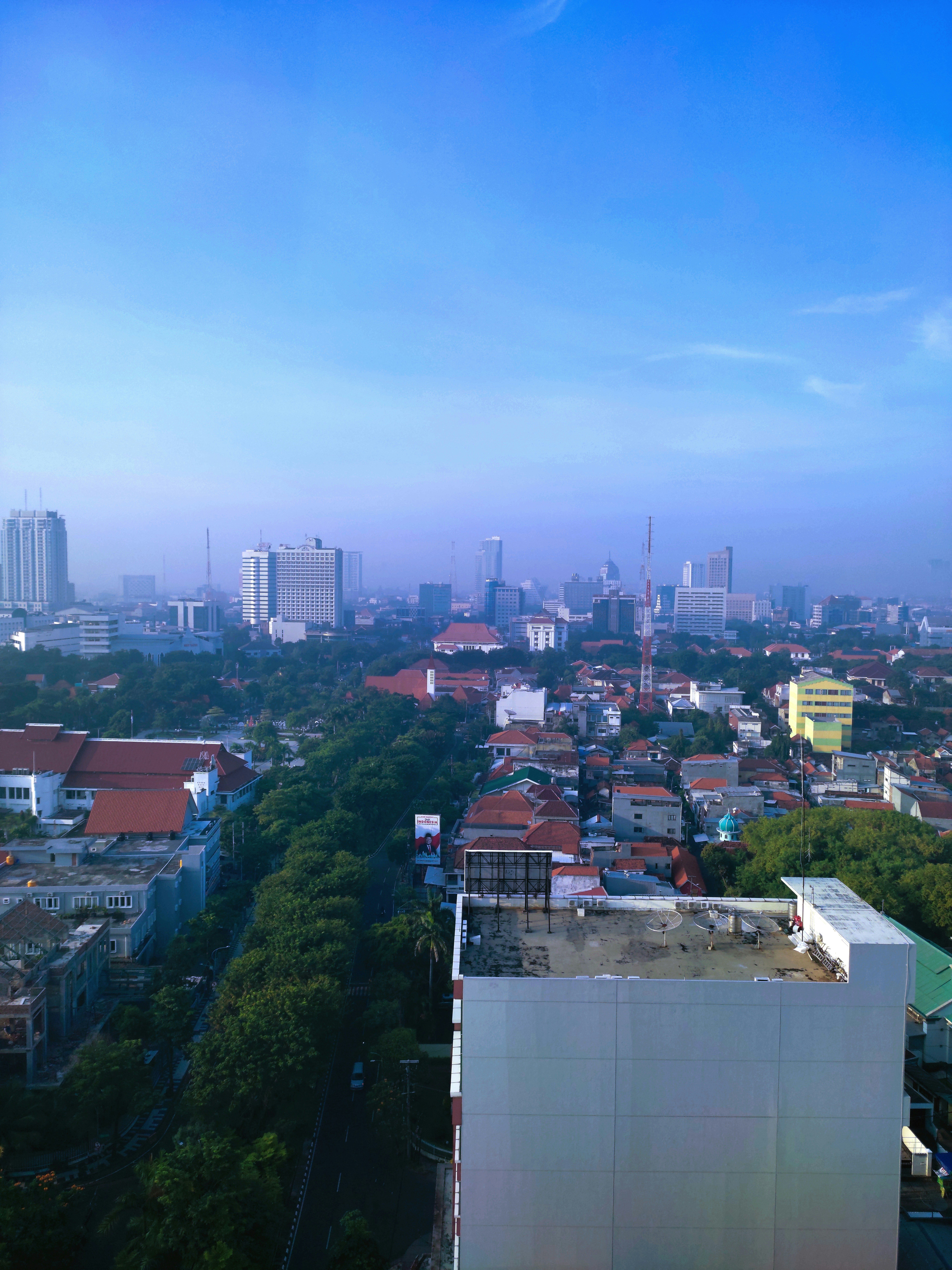 A panoramic view of a bustling cityscape at dawn, showcasing a blend of modern skyscrapers and traditional architecture under a clear blue sky.
