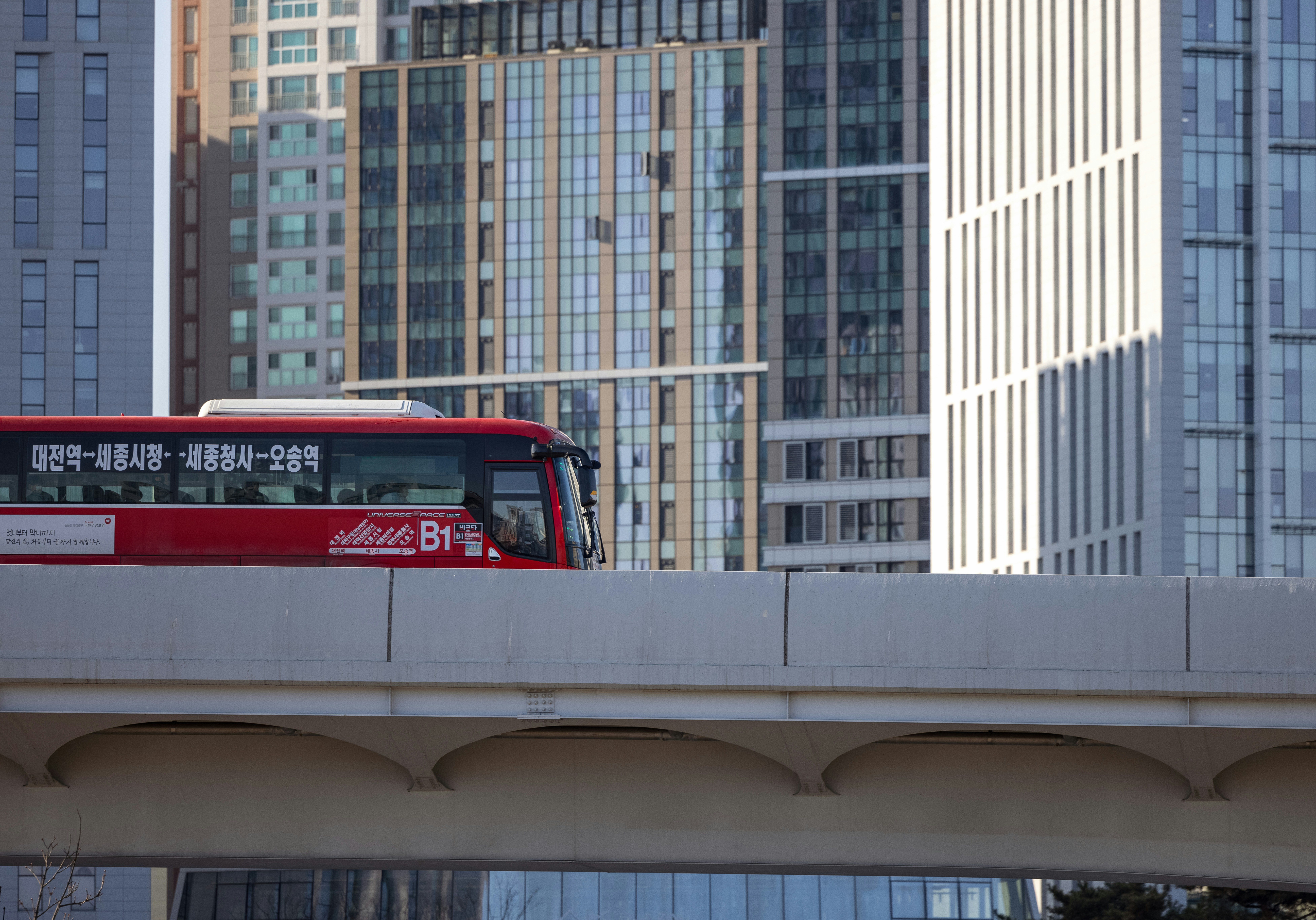 A red bus driving over a bridge in a city photo – Free City Image on ...