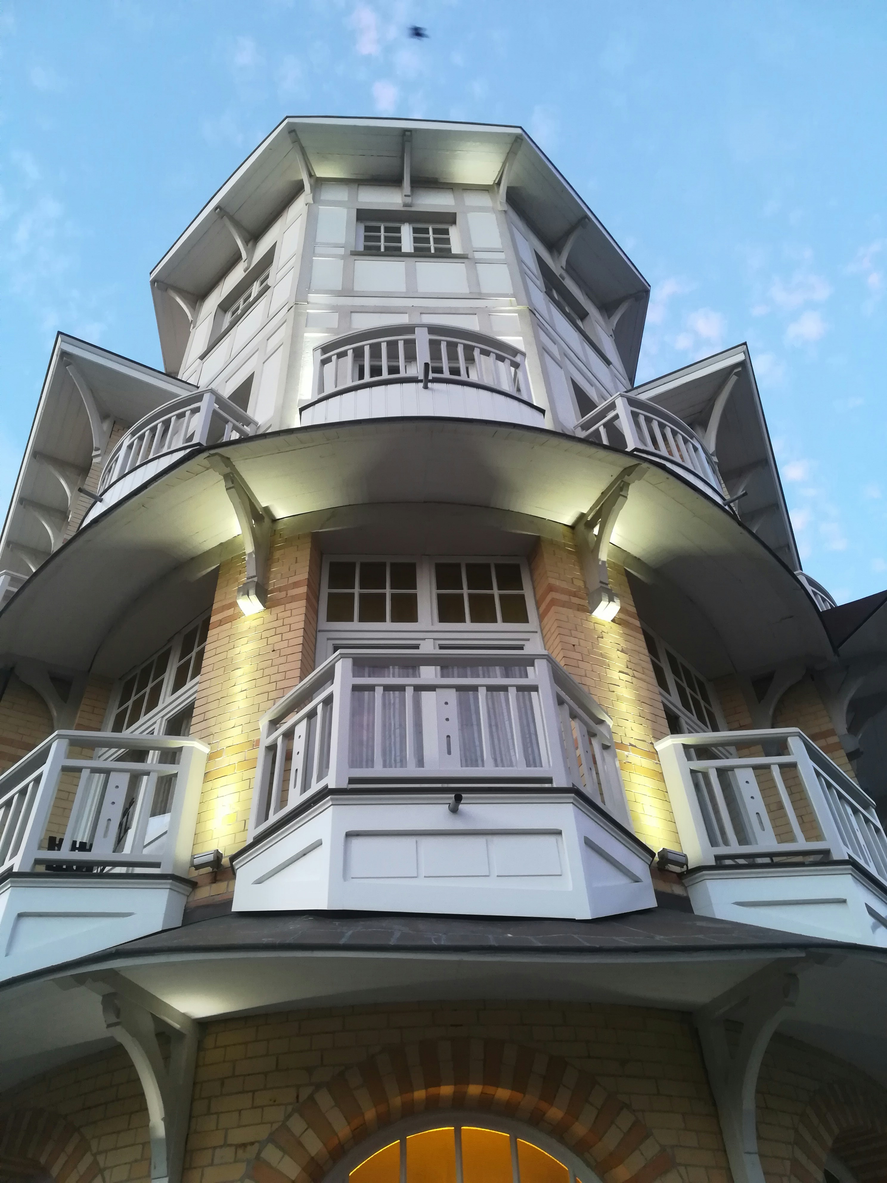 Upward view of a multi-story Victorian-style building with intricate balconies against a twilight sky.