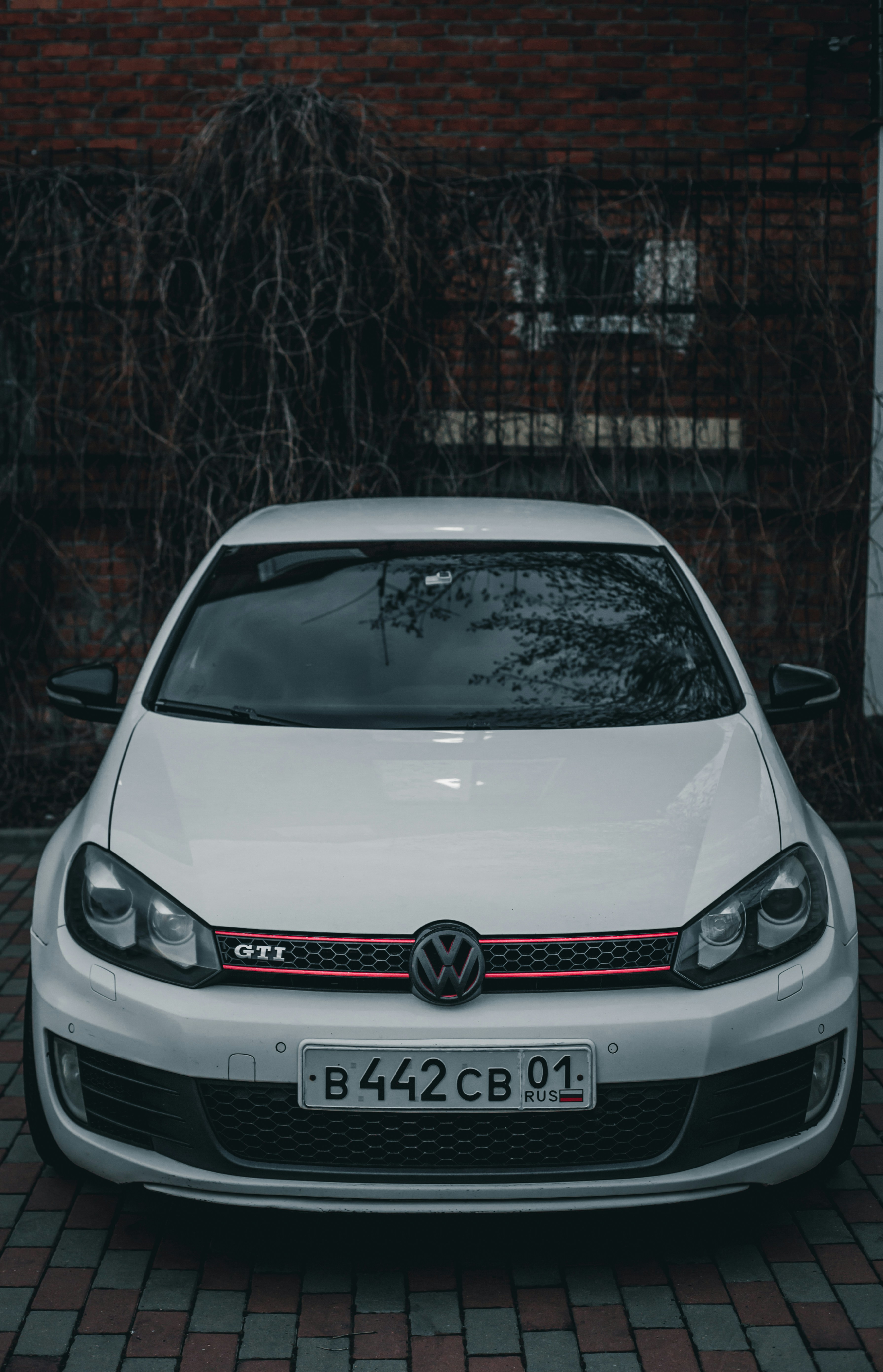 Center Stage: White VW GTI Front View Framed by Brick and Ivy