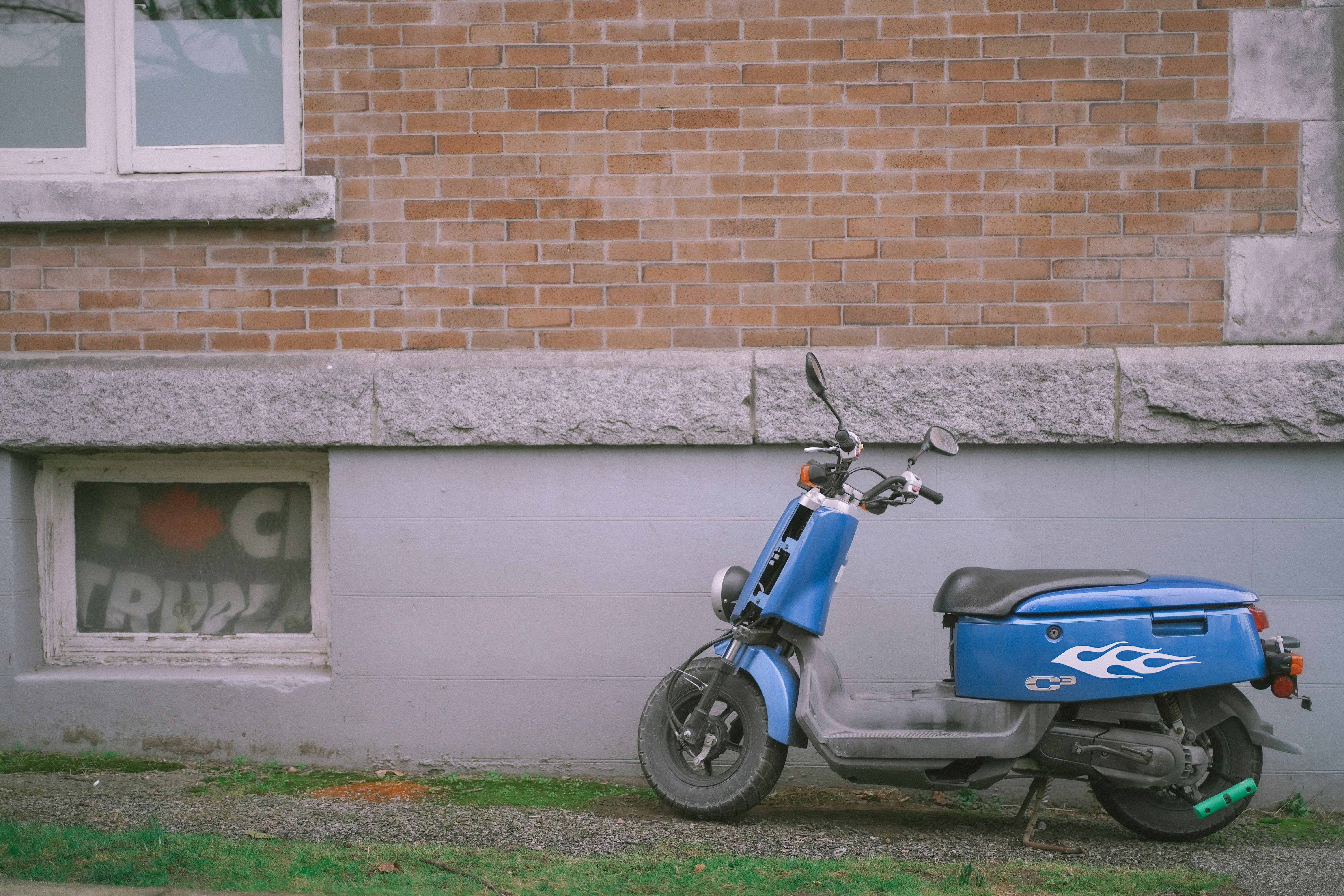 a blue scooter parked in front of a brick building
