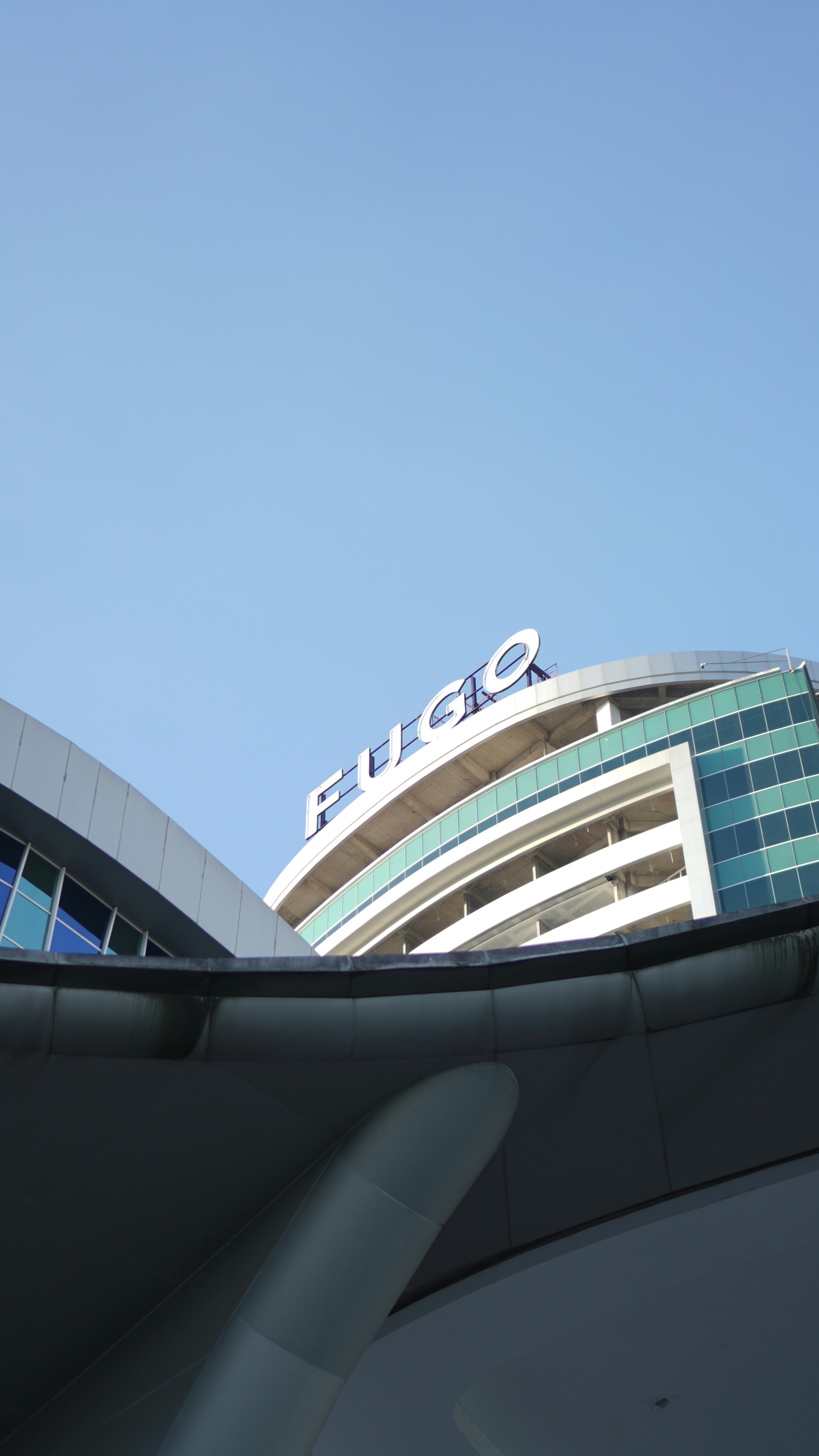 Modern high-rise building with a prominent 'FUGO' sign against a clear blue sky.
