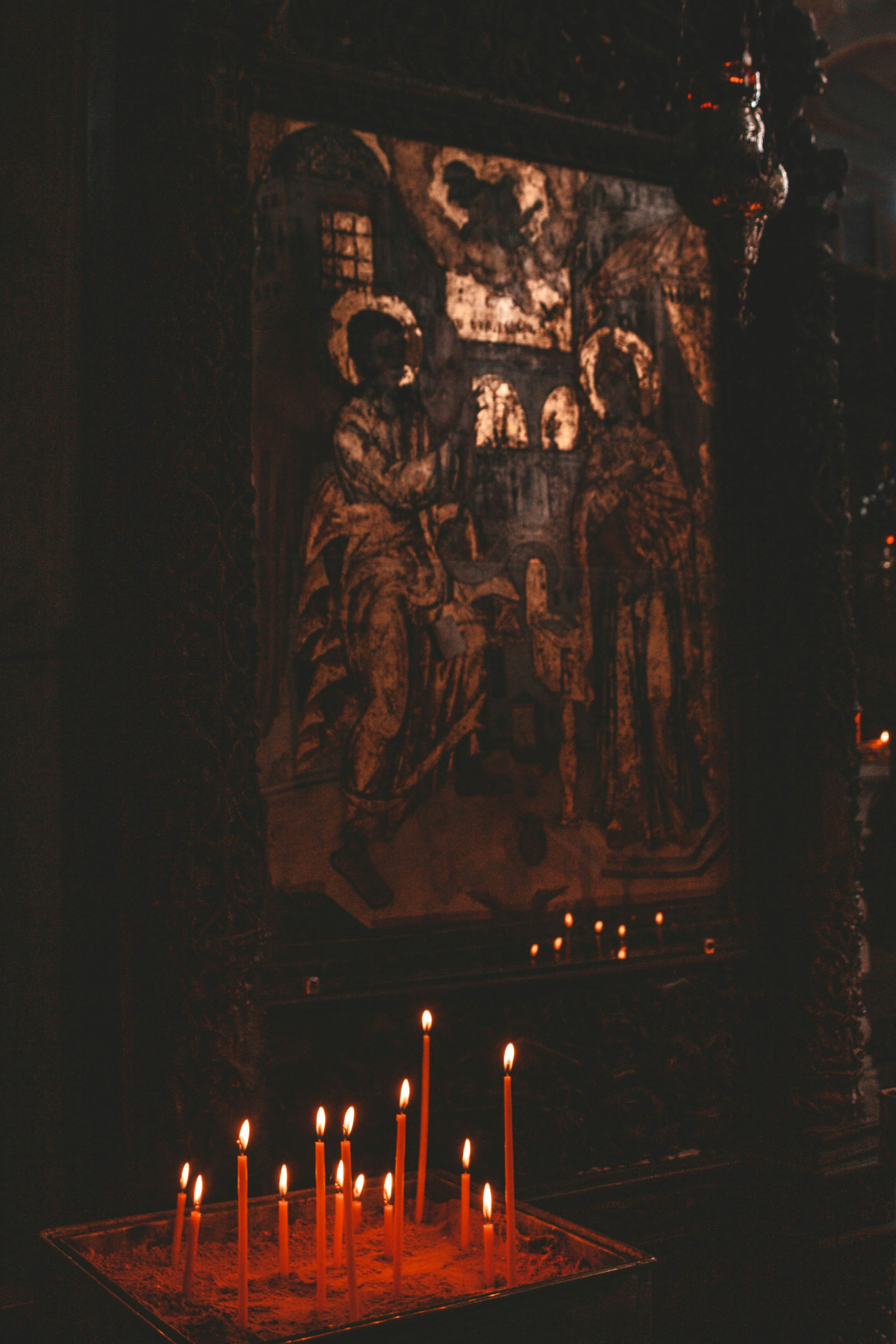 a group of lit candles sitting in front of a painting