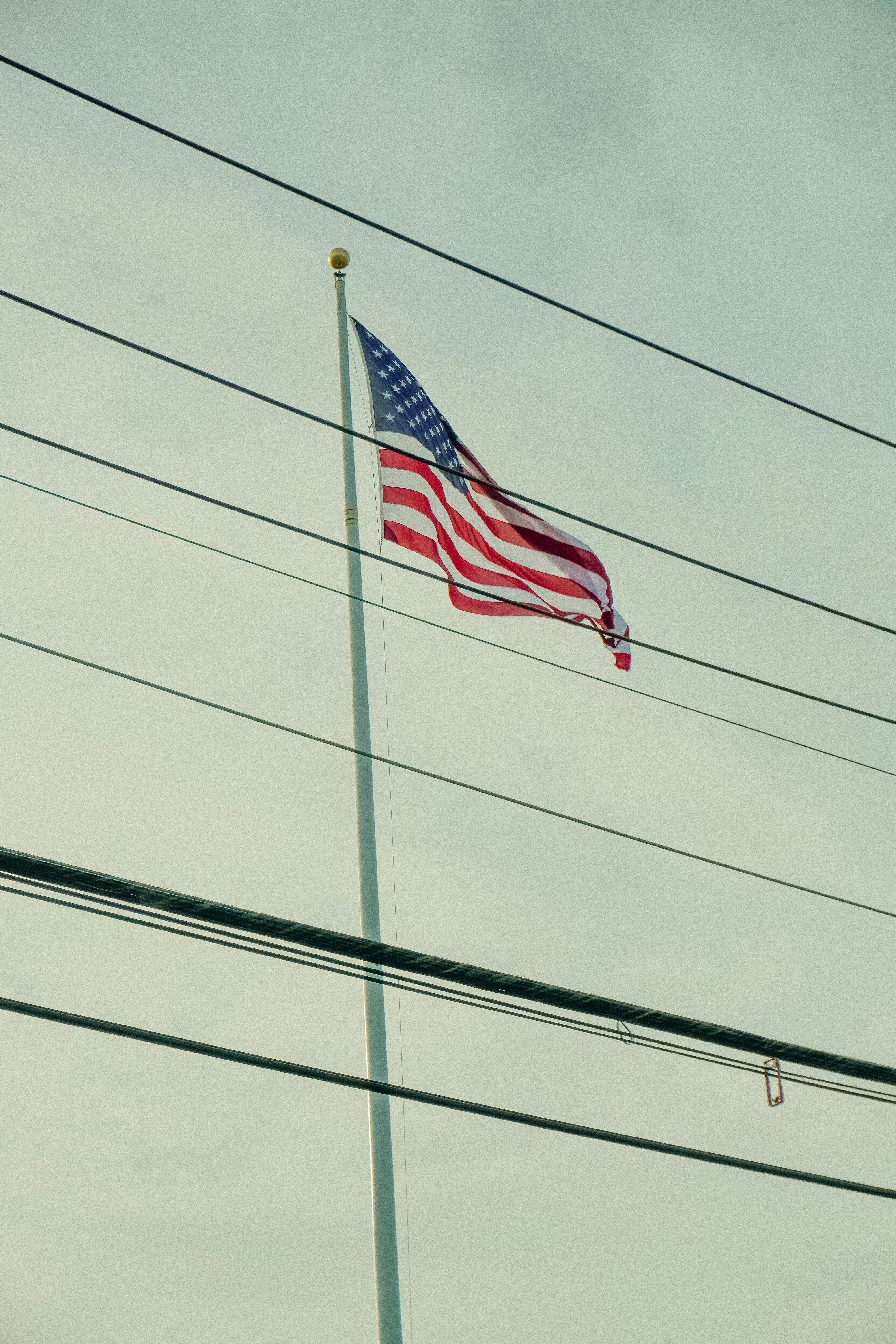 an american flag on a pole with power lines in the background
