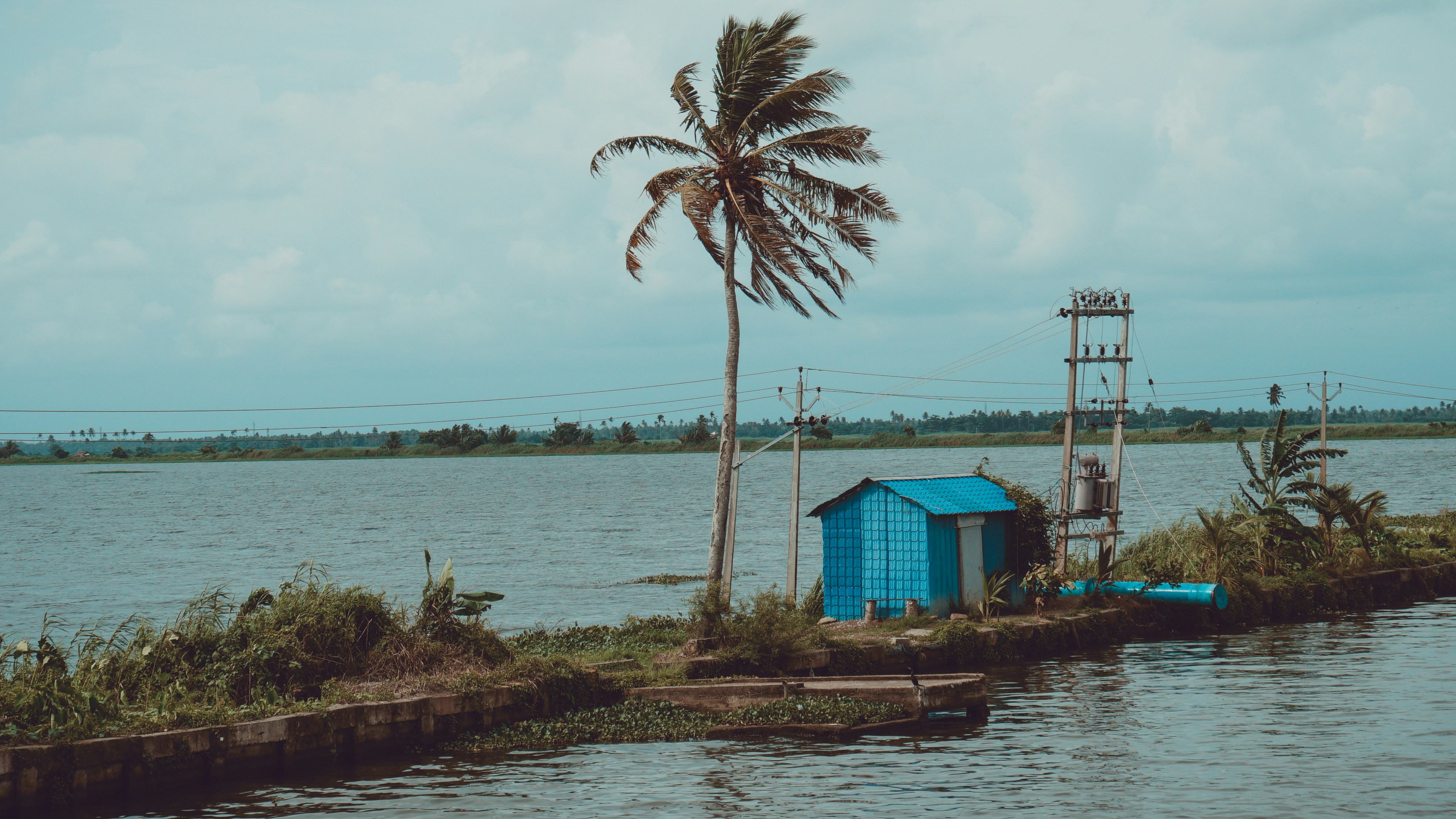 A blue shack sitting on the side of a body of water photo – Free Water ...