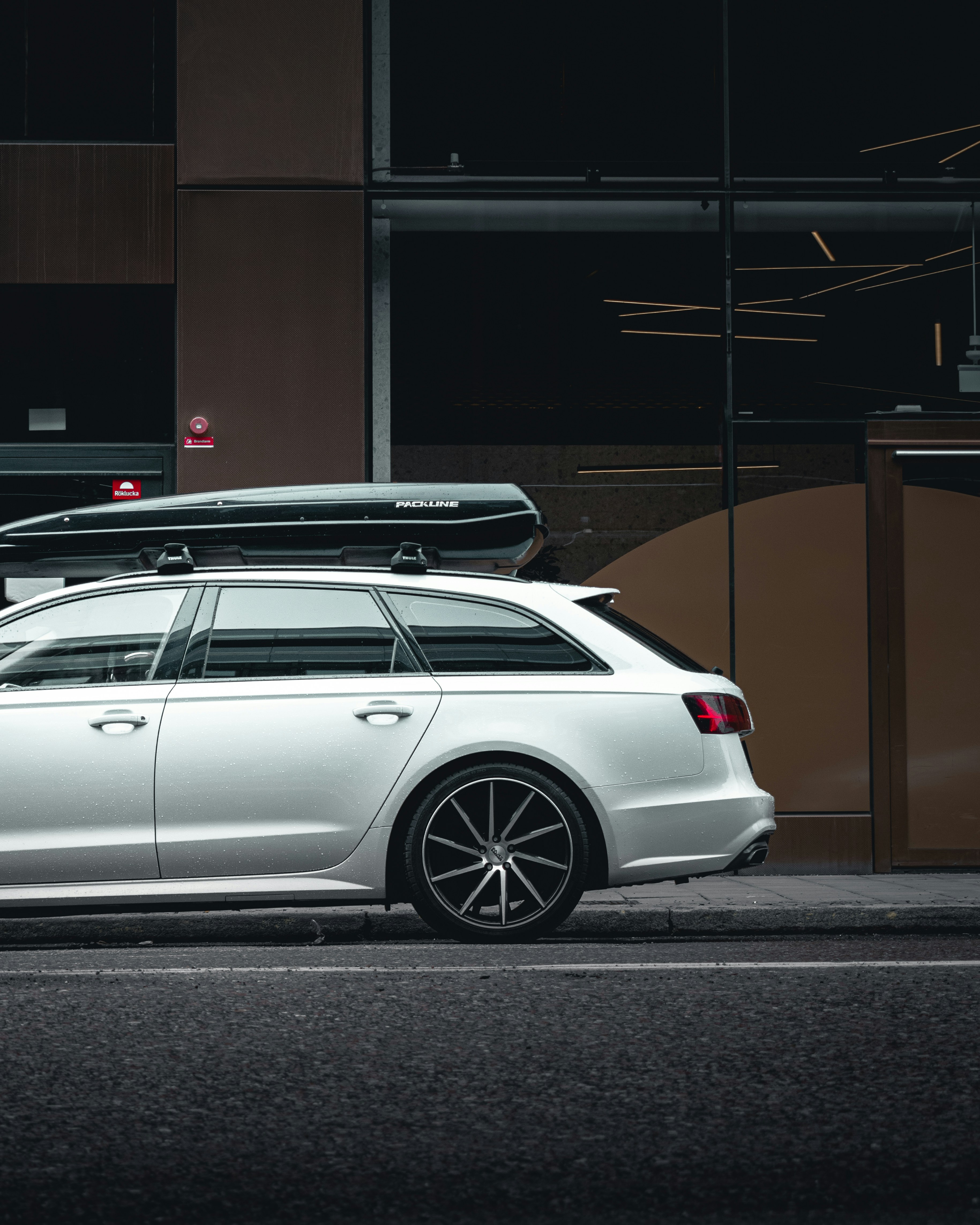 Urban Quiet: A Silver Wagon Beneath a Modern Glass Facade