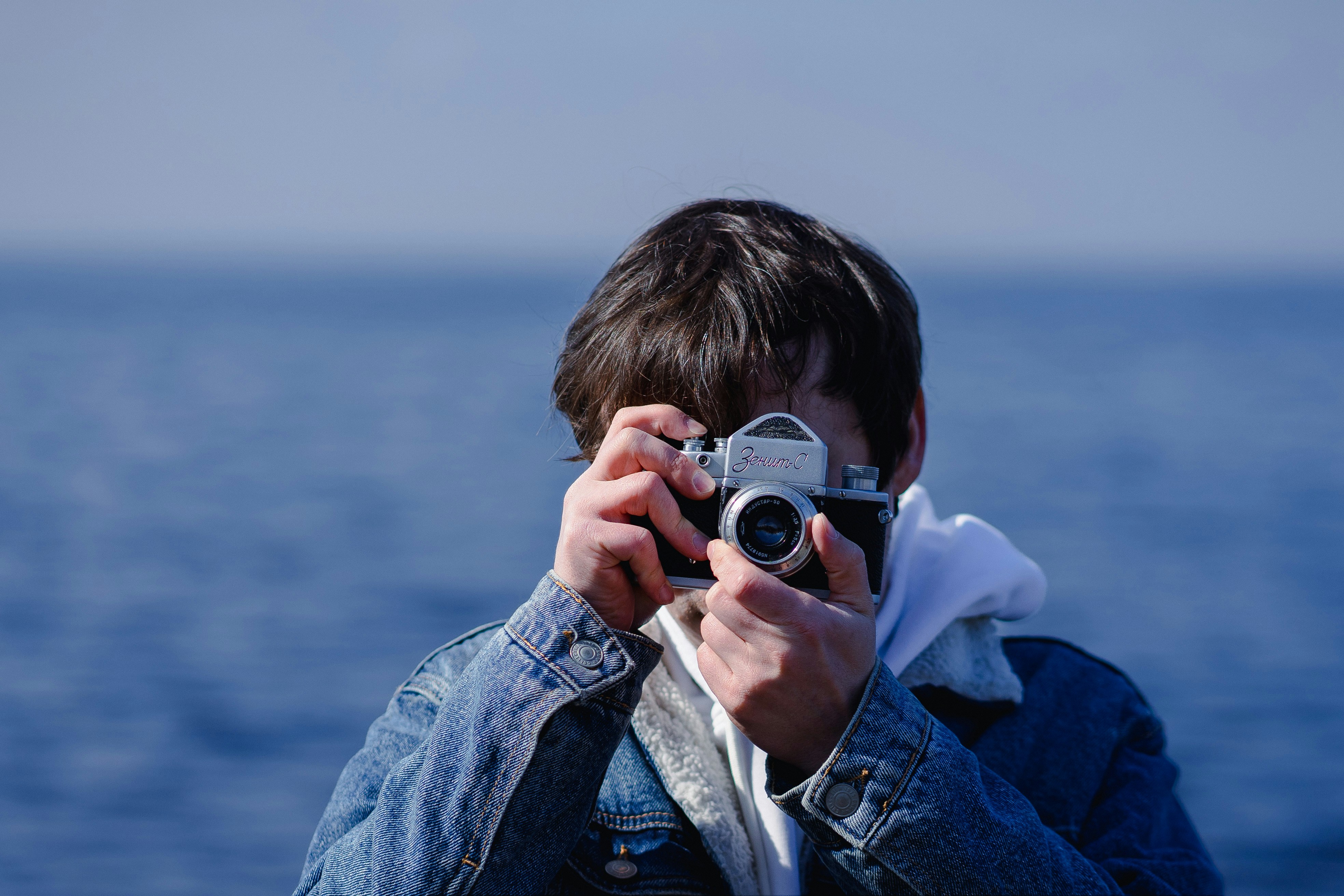 Focused Frame: A Youth with a Silver Capped Camera by the Sea