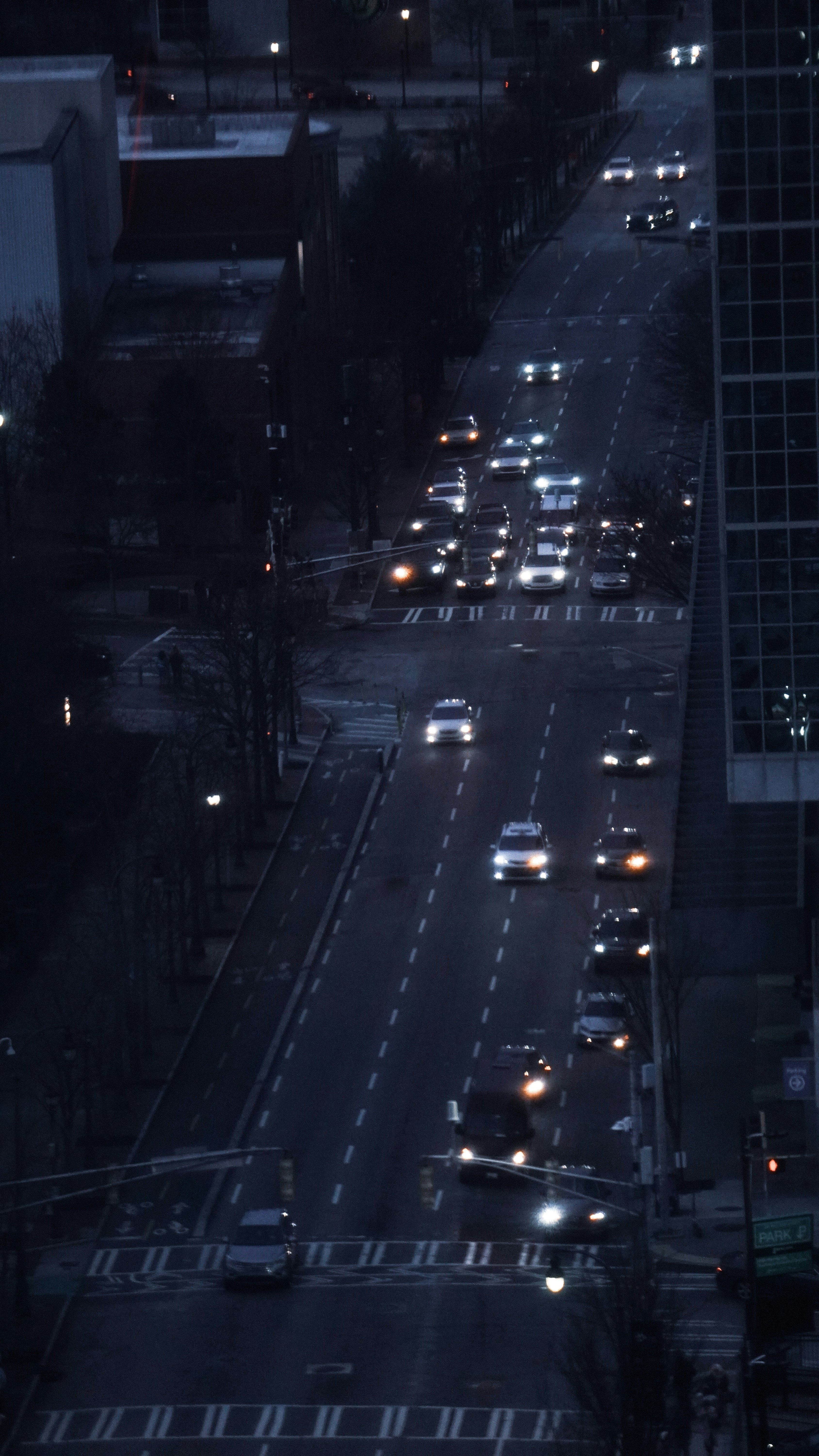City street illuminated by headlights and streetlights during twilight, showcasing the flow of evening traffic.