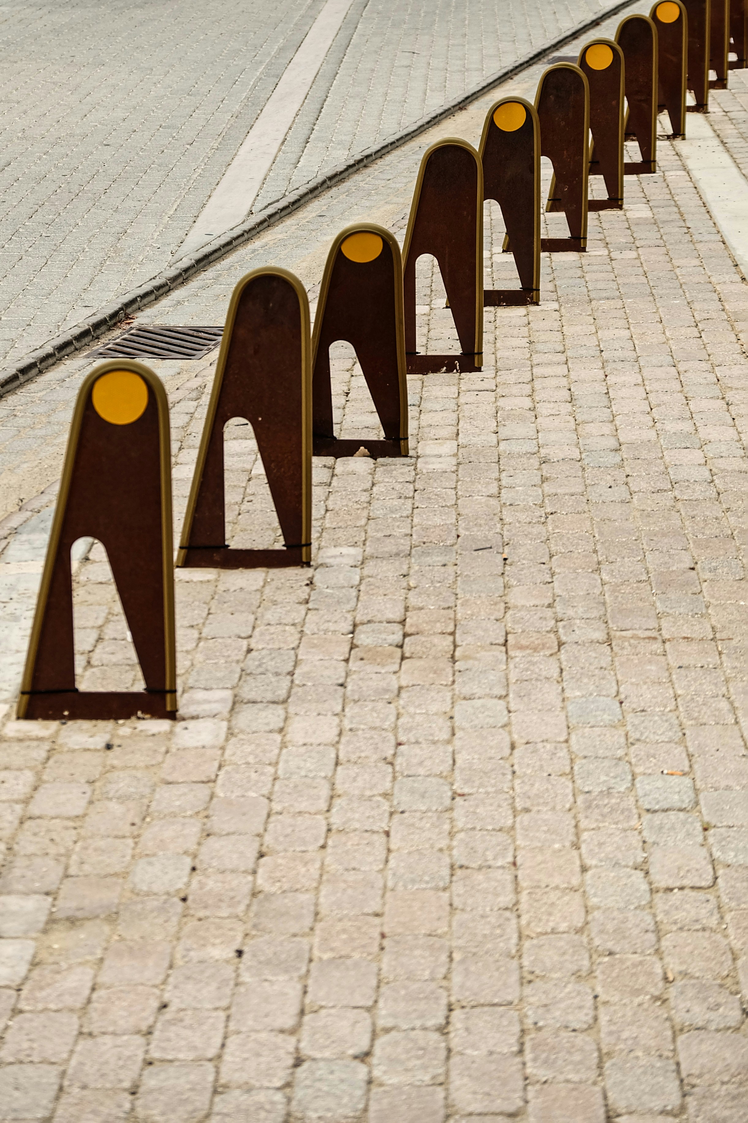 Yellow-Capped Bollards Lead the Cobbled Path in Diagonal Perspective