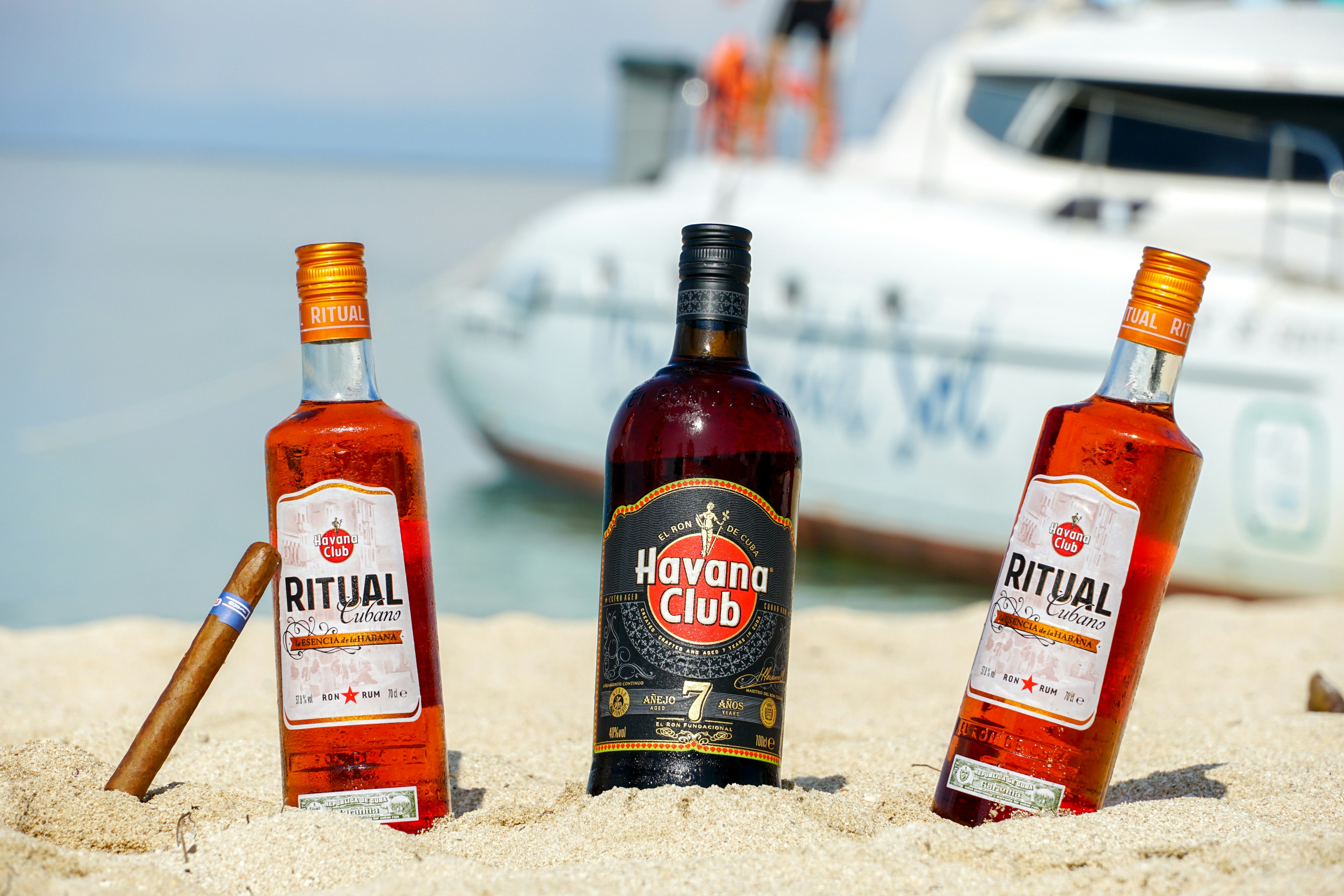 A couple of bottles of liquor sitting on top of a sandy beach photo ...