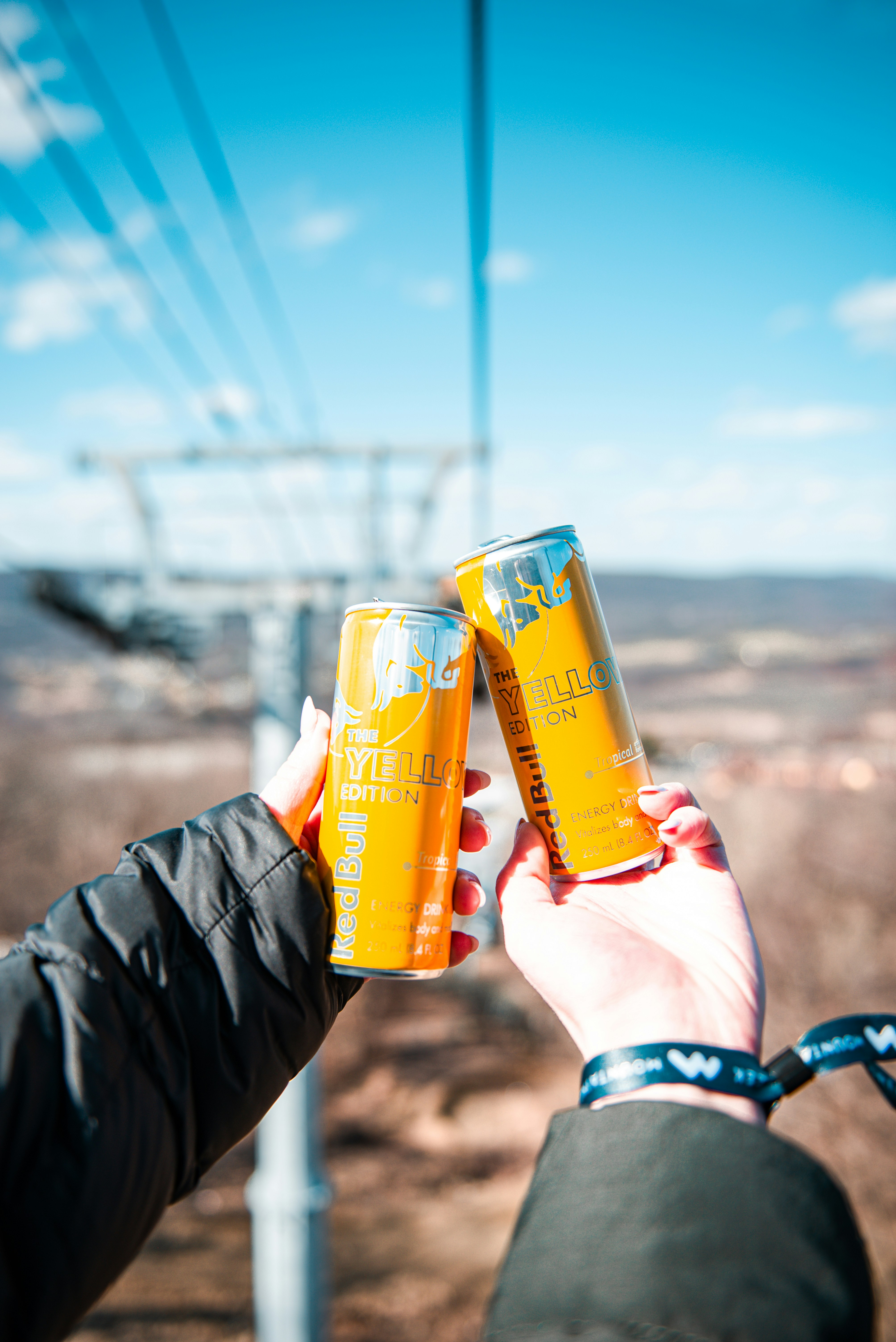 Raising Energy: Two Yellow Edition Cans Toasted Against Blue Sky