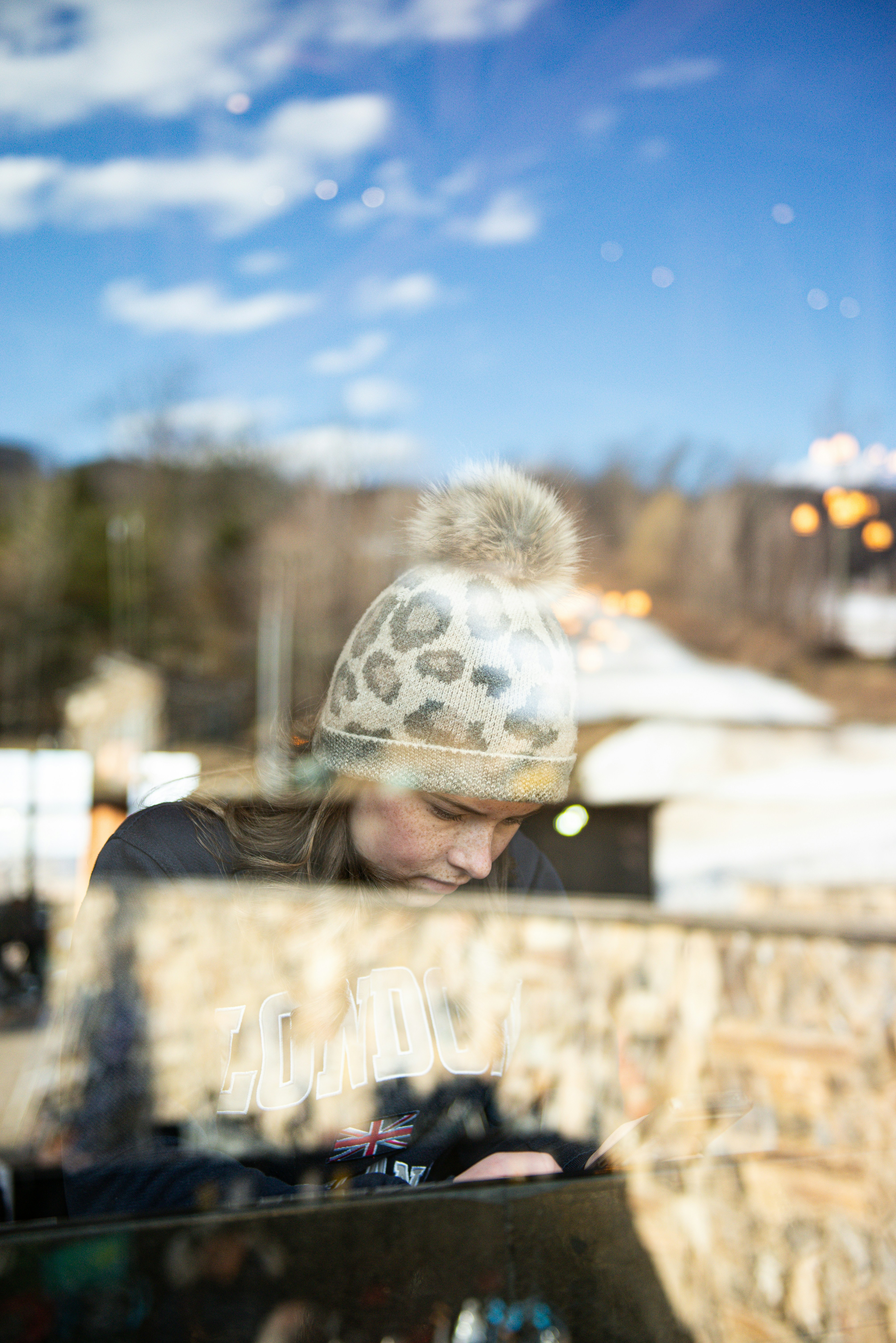 a woman looking at her cell phone through a window