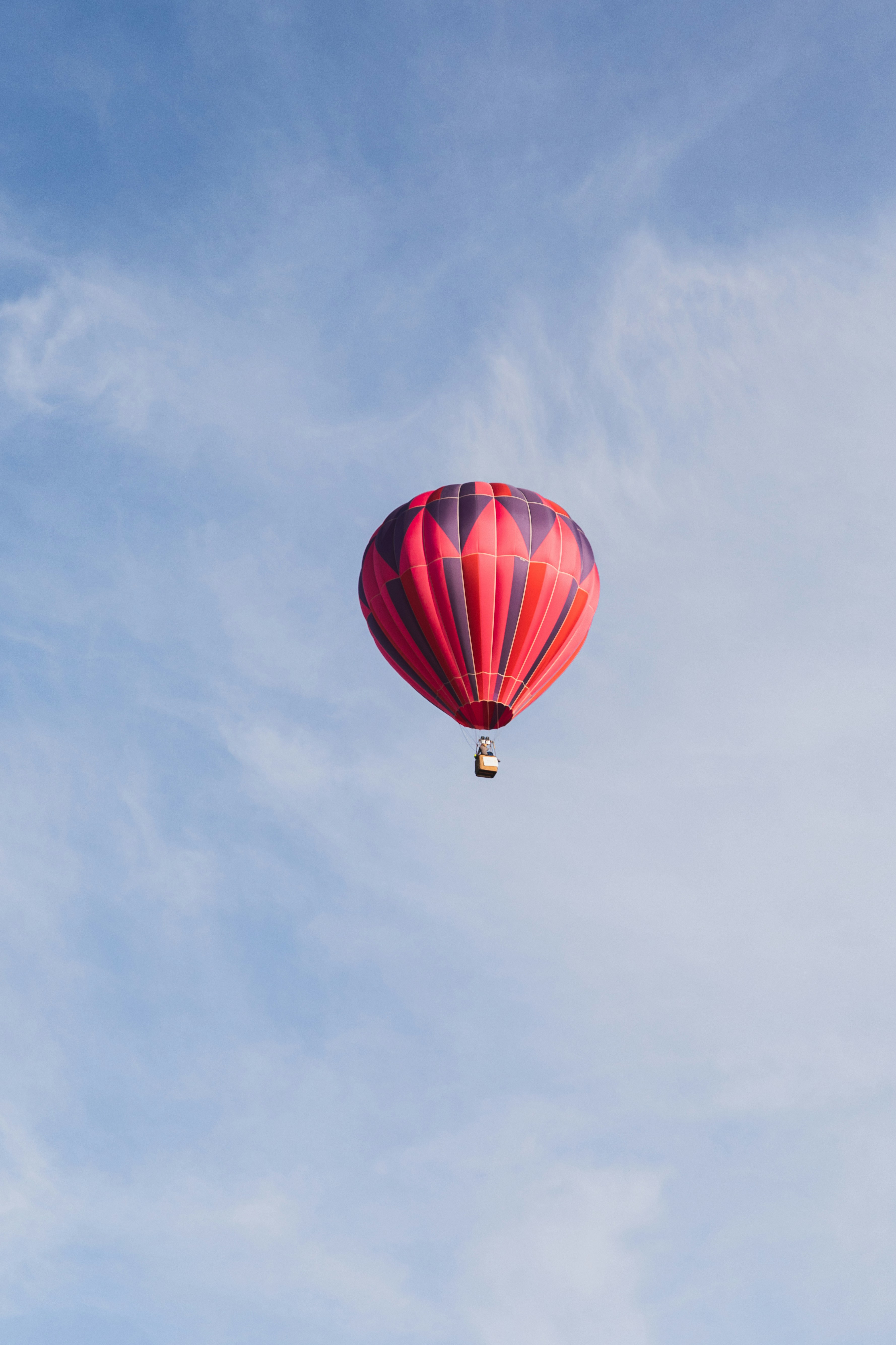 A red hot air balloon flying through a blue sky photo – Free Lake Image on Unsplash