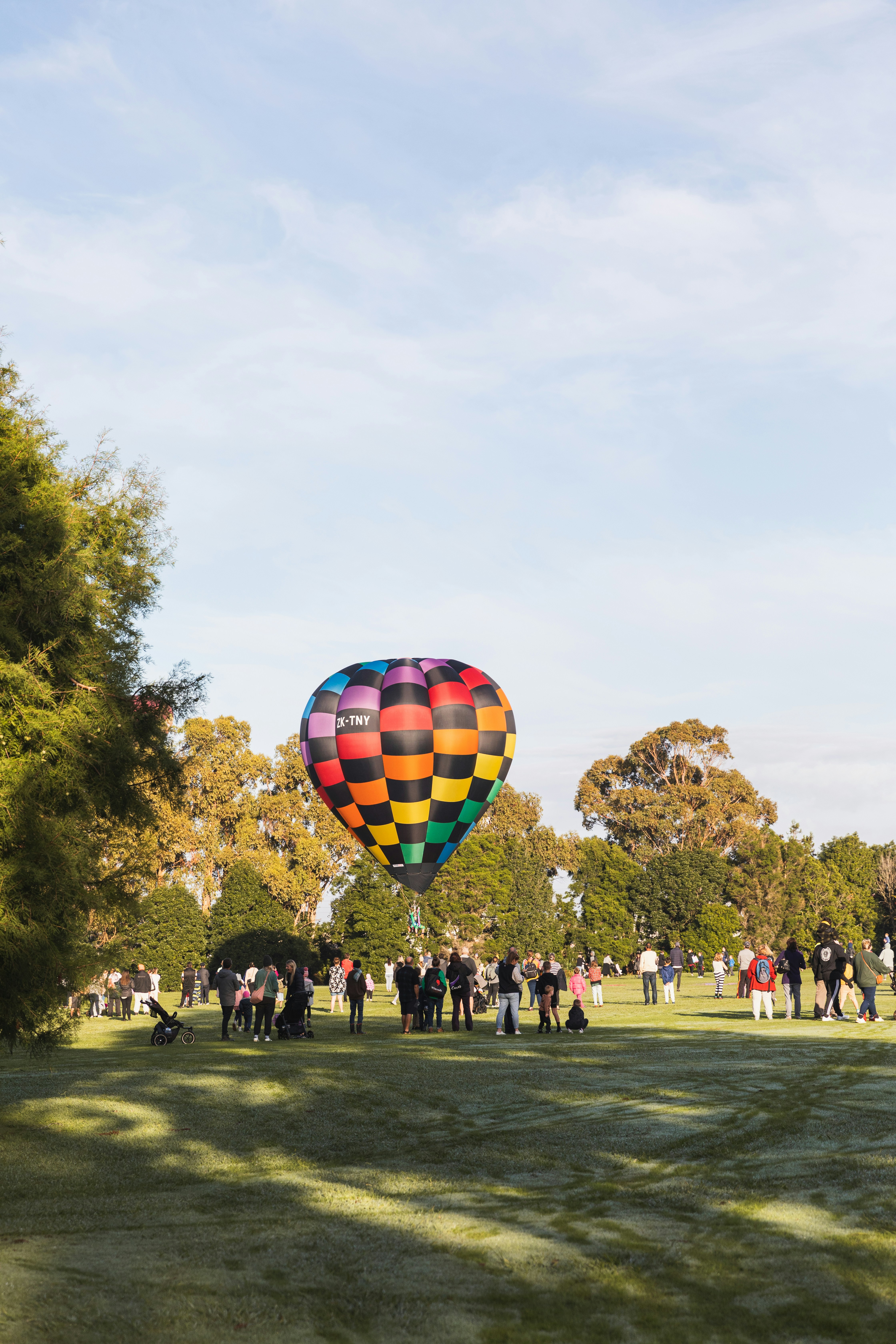 A group of people standing around a colorful hot air balloon photo ...