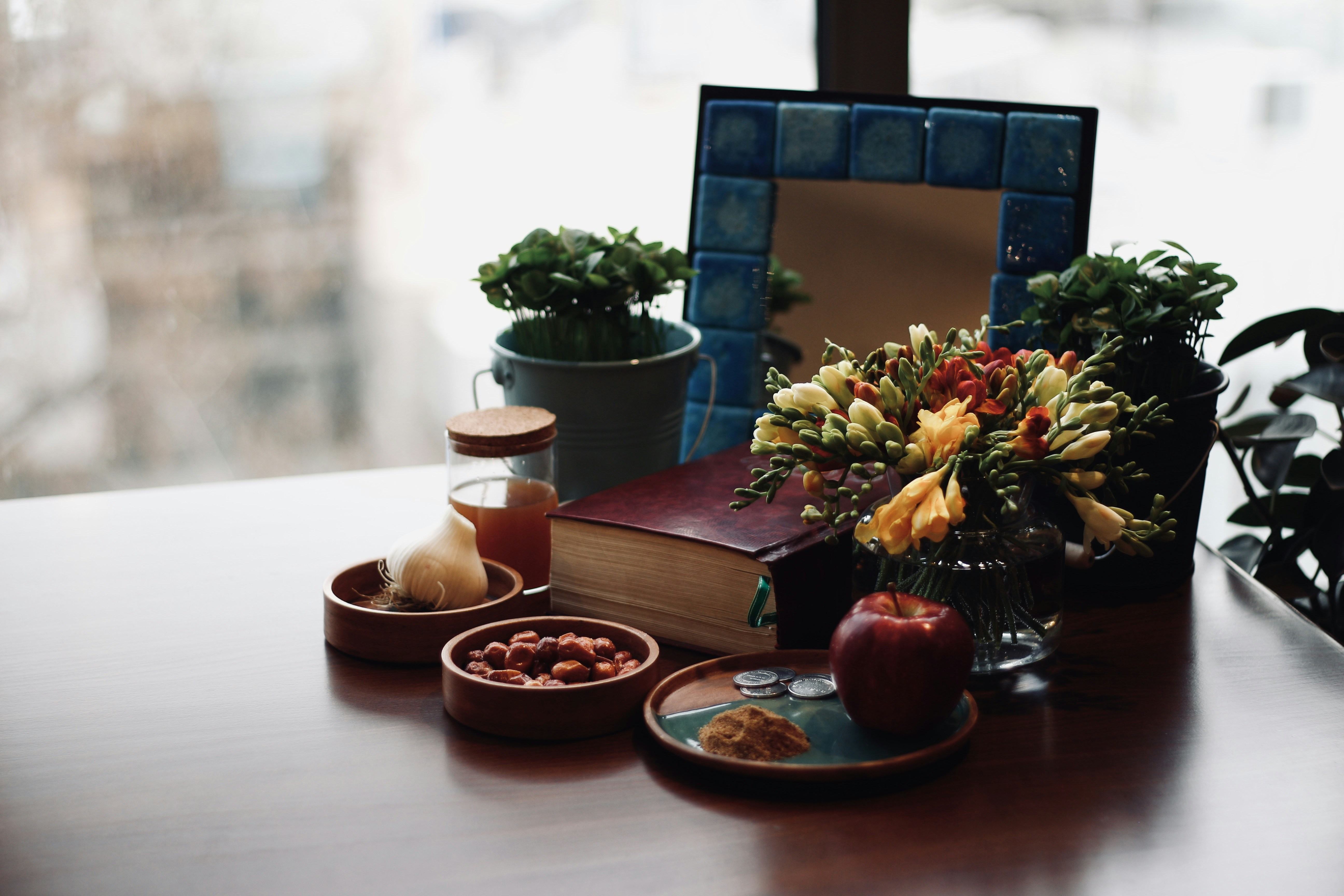 Still life at dusk: a quiet tabletop vignette with flowers, fruit, and a reflective mosaic