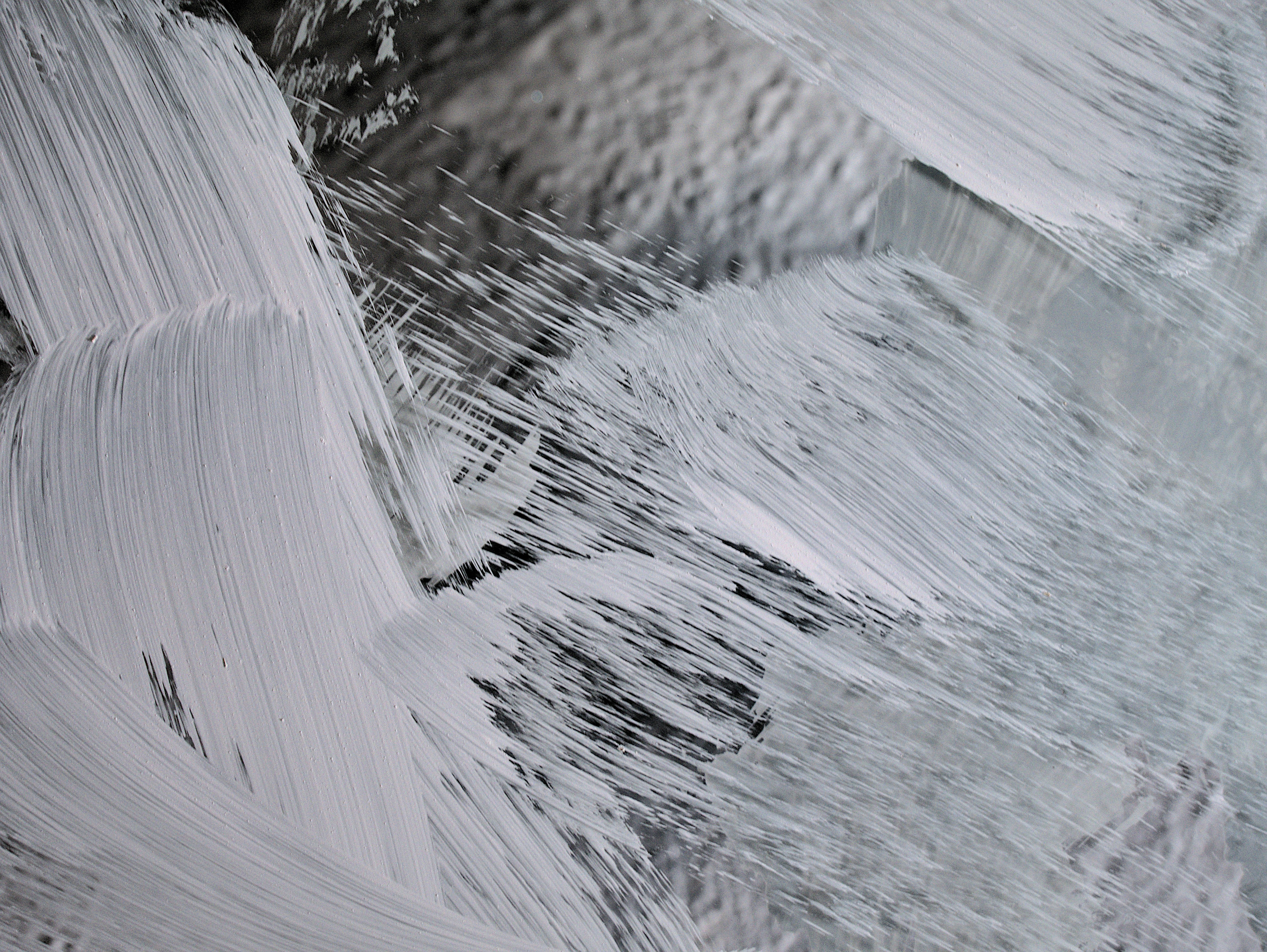 Abstract white paint strokes layered intricately on a glass surface.