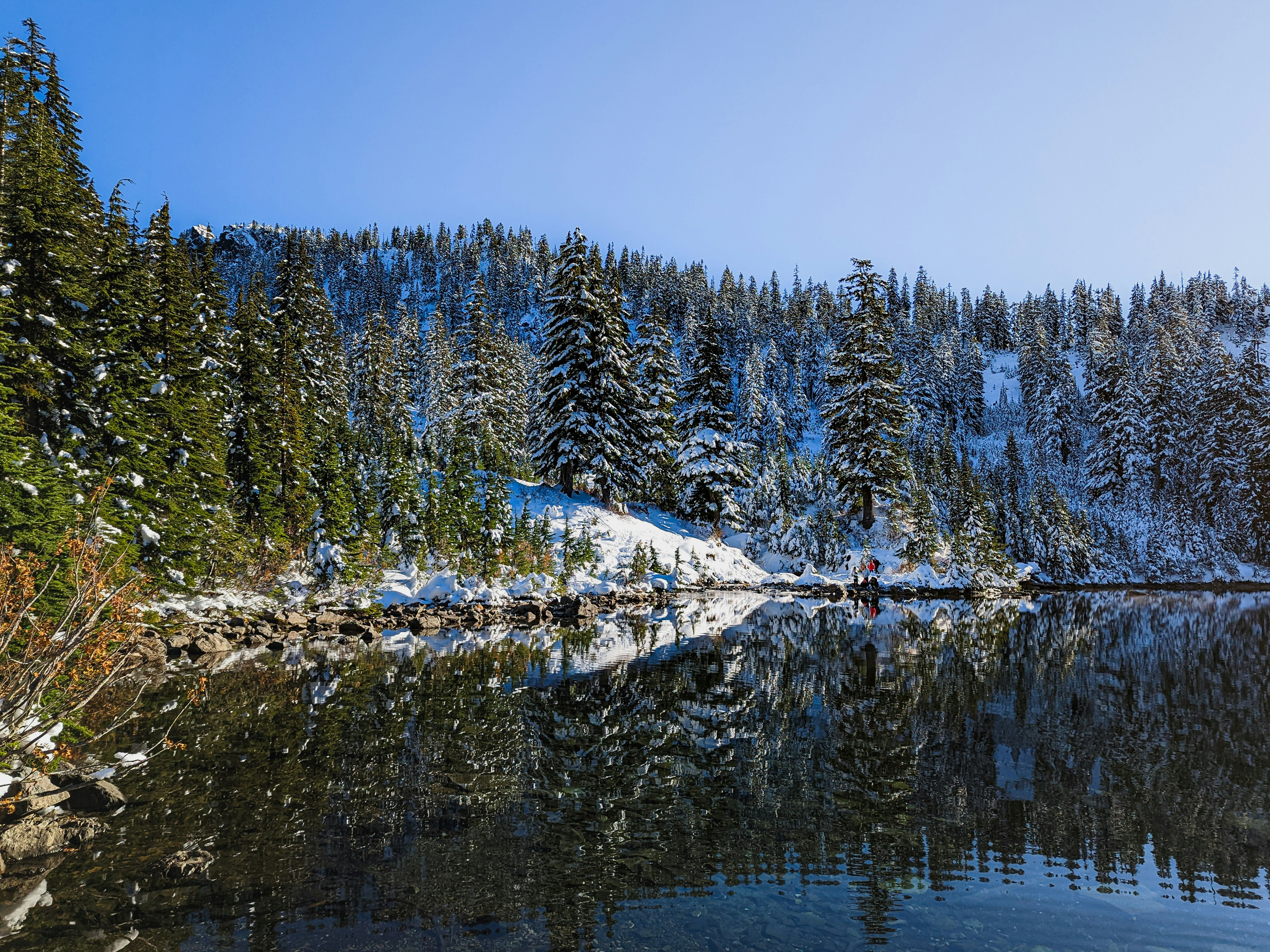 Foto Un lago rodeado de montañas cubiertas de nieve y árboles – Imagen ...