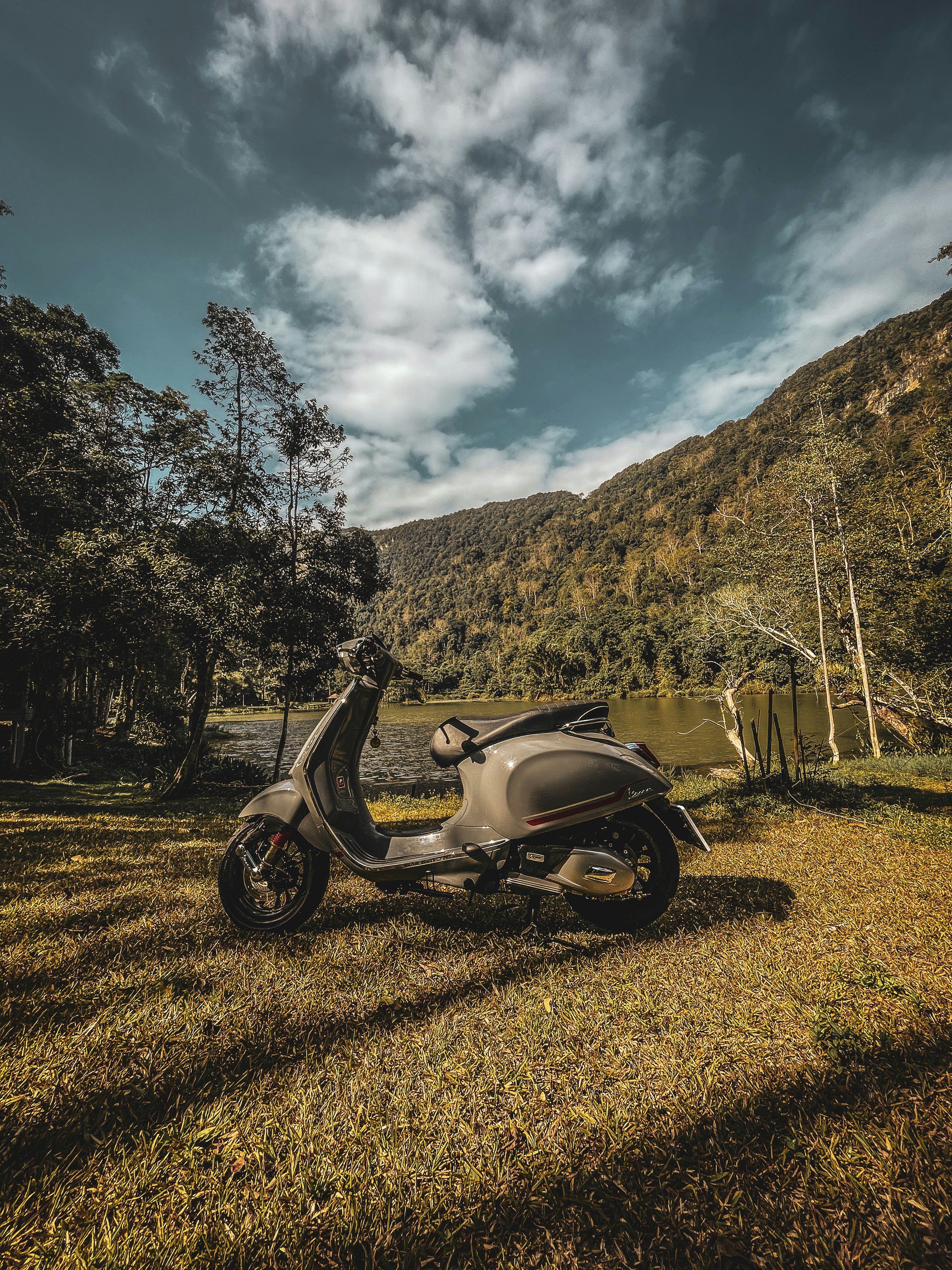 a scooter parked in the grass near a lake