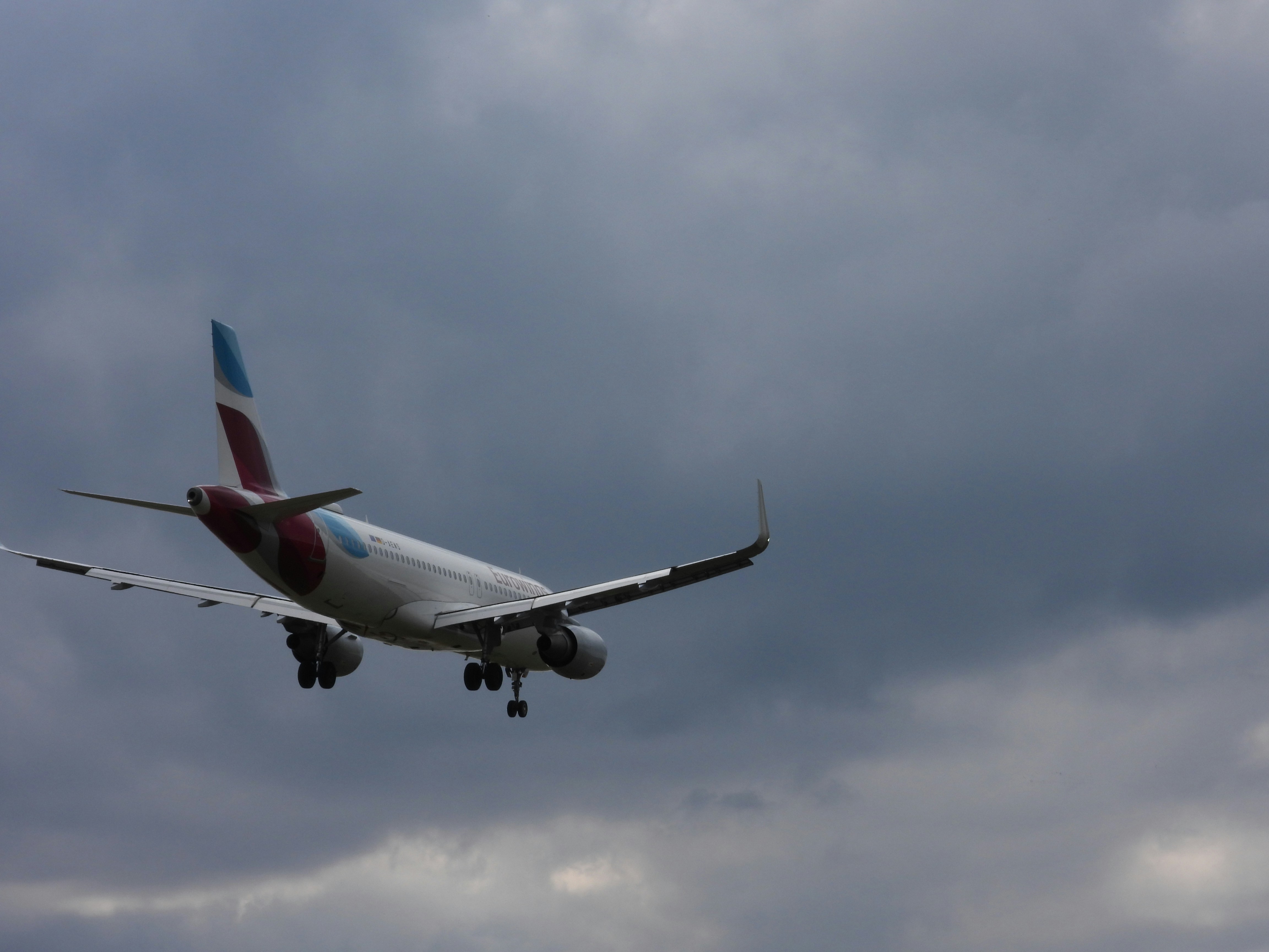 Commercial airplane descending through a dramatic sky filled with dark clouds.