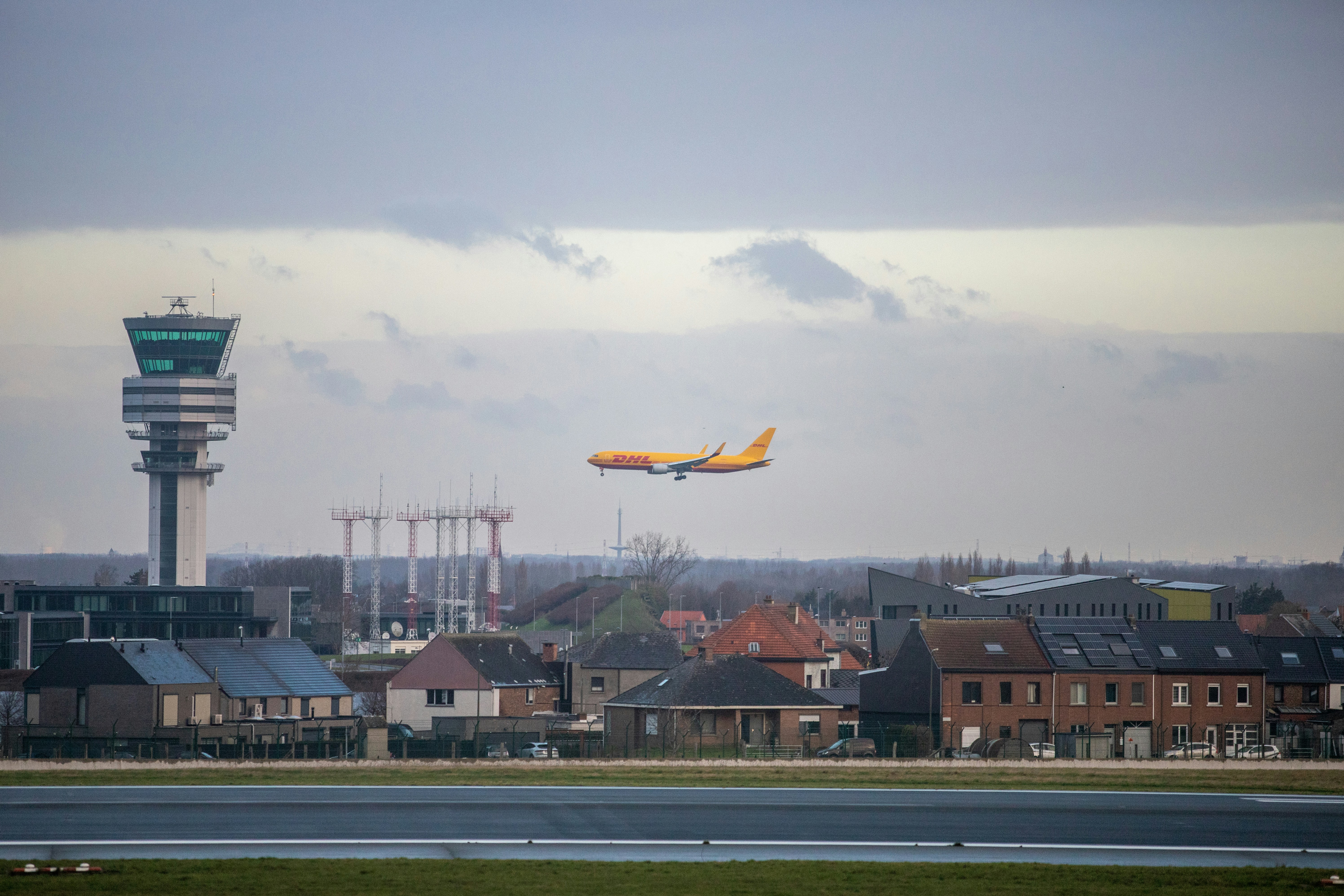 Plane spotting at Brussels Airport early in the morning | a large jetliner flying over a city under a cloudy sky