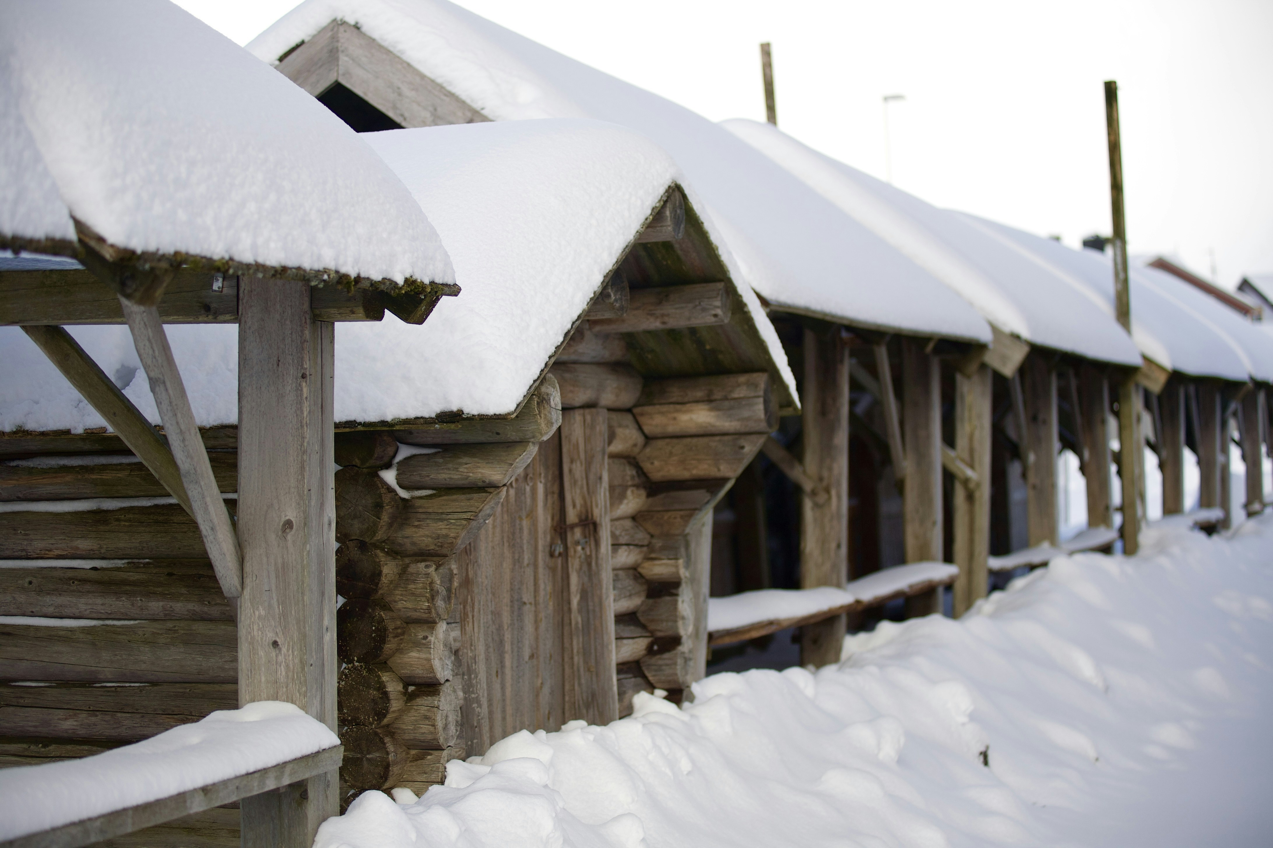 Wooden structures blanketed in snow, showcasing a serene winter landscape with a focus on rustic architecture.