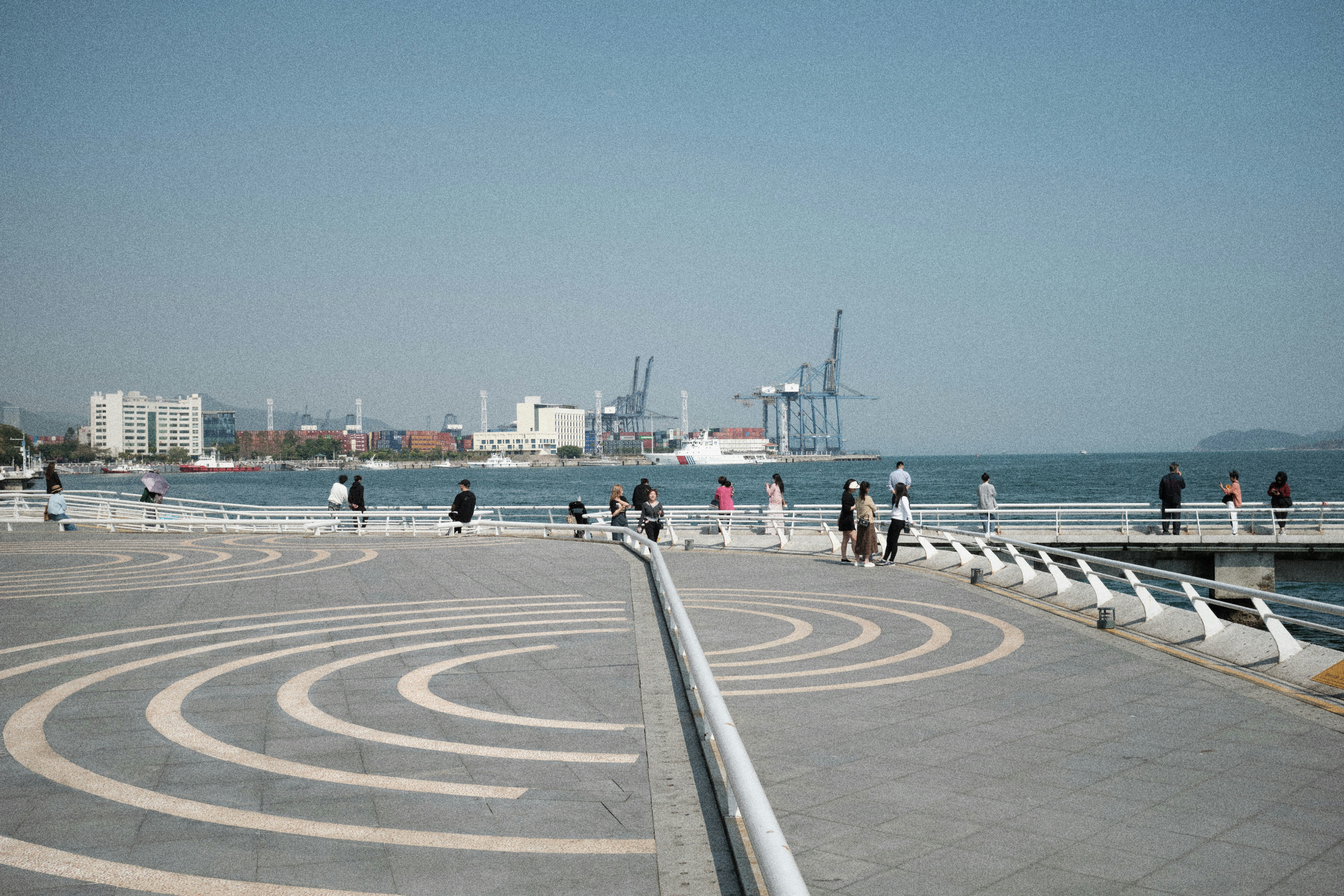 a group of people standing on a pier next to the ocean