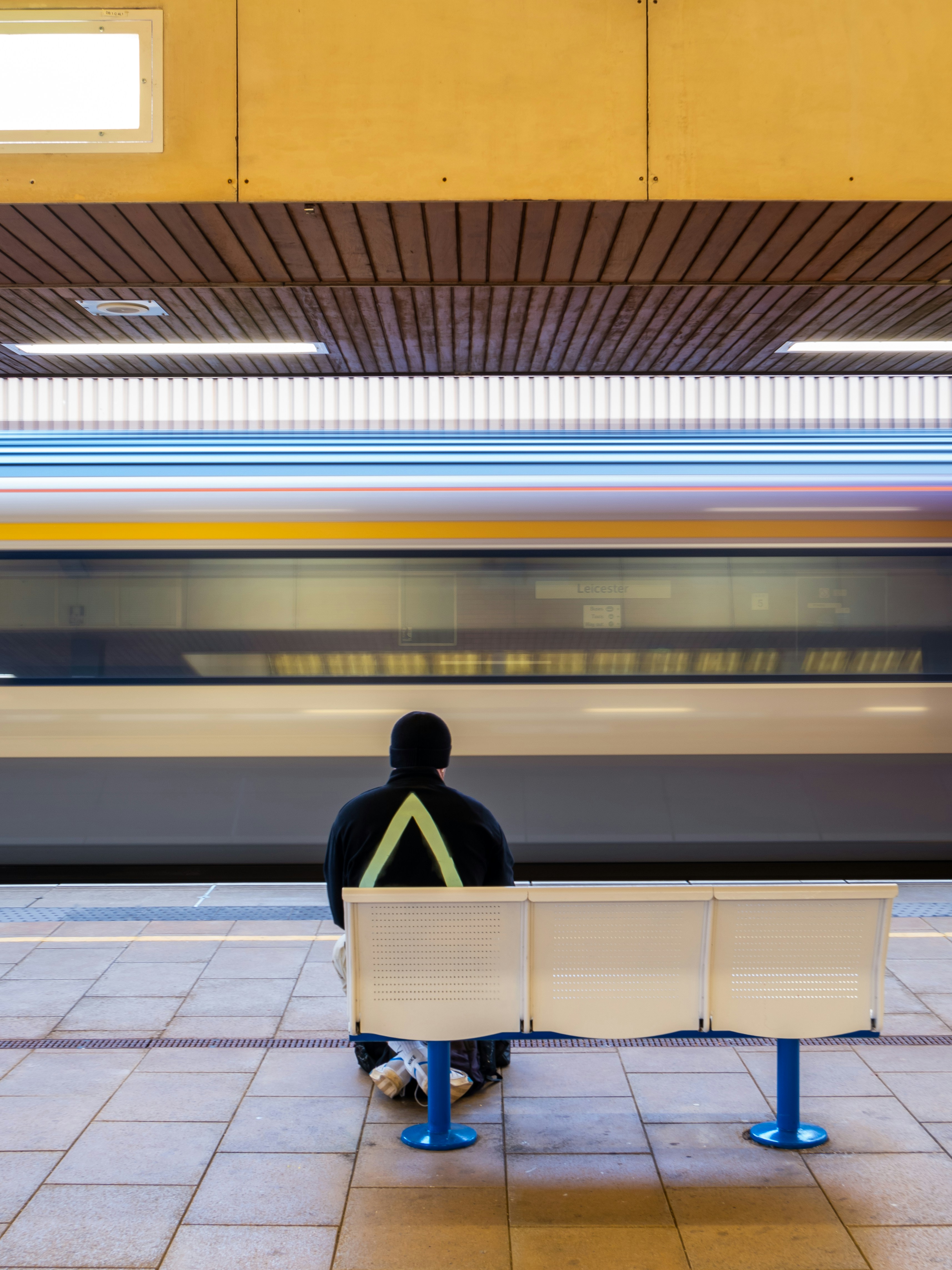 Benchbound: A Quiet Figure Anchored as Neon Blur Races By