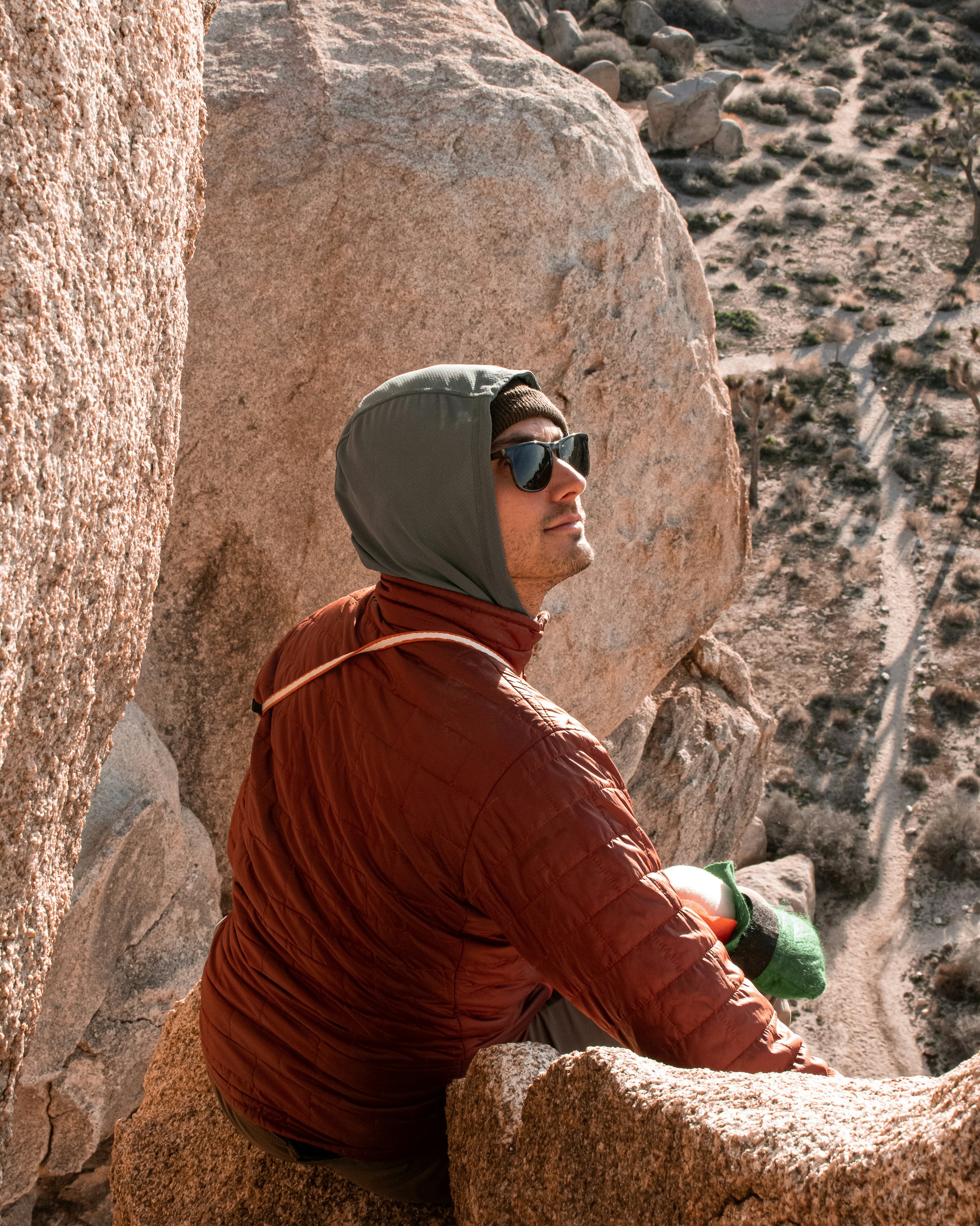 A climber resting against a rock formation, gazing thoughtfully at the landscape. The scene captures the essence of adventure and tranquility in nature.